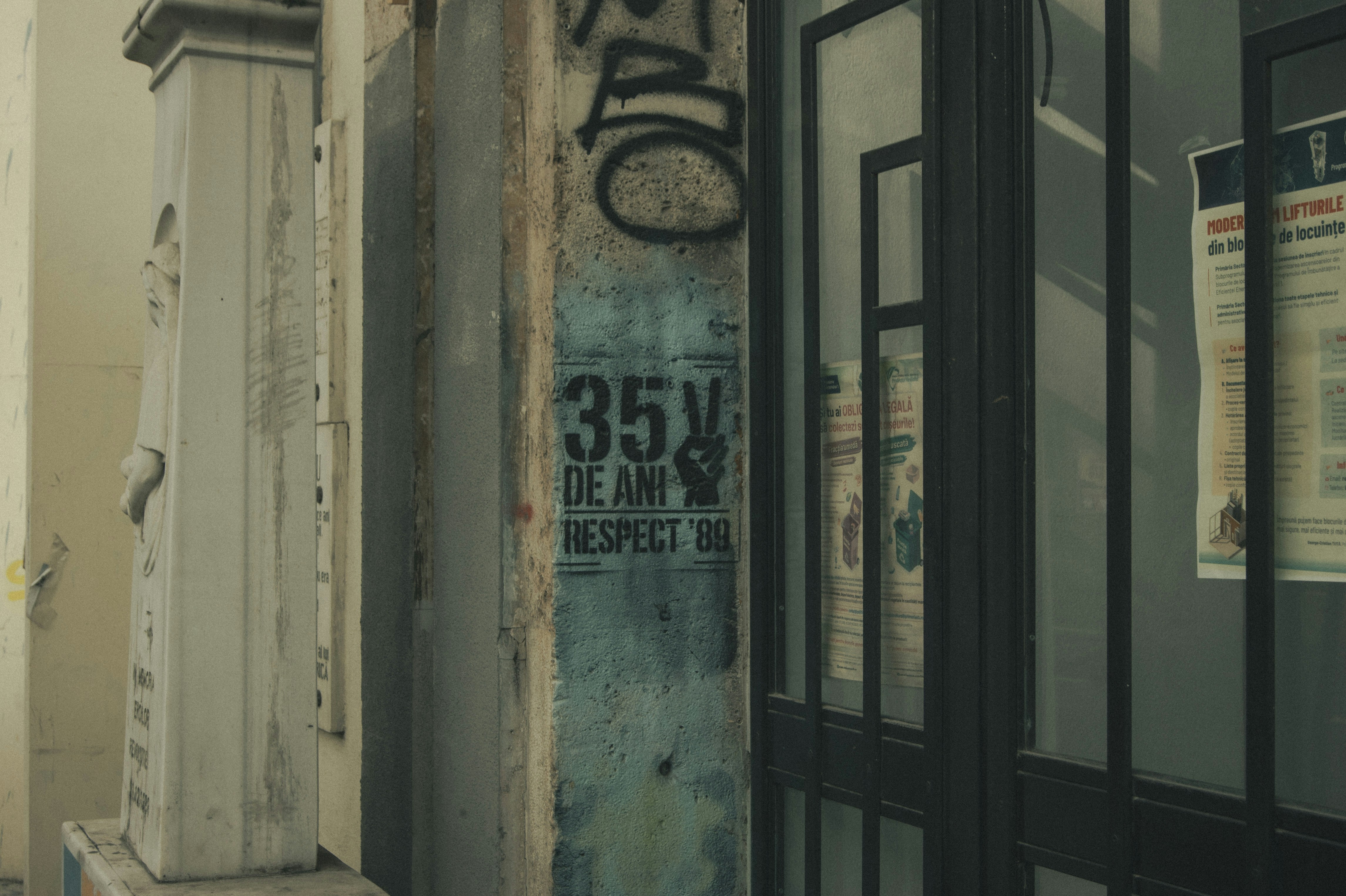 Weathered doorway and graffiti-streaked column on a narrow street