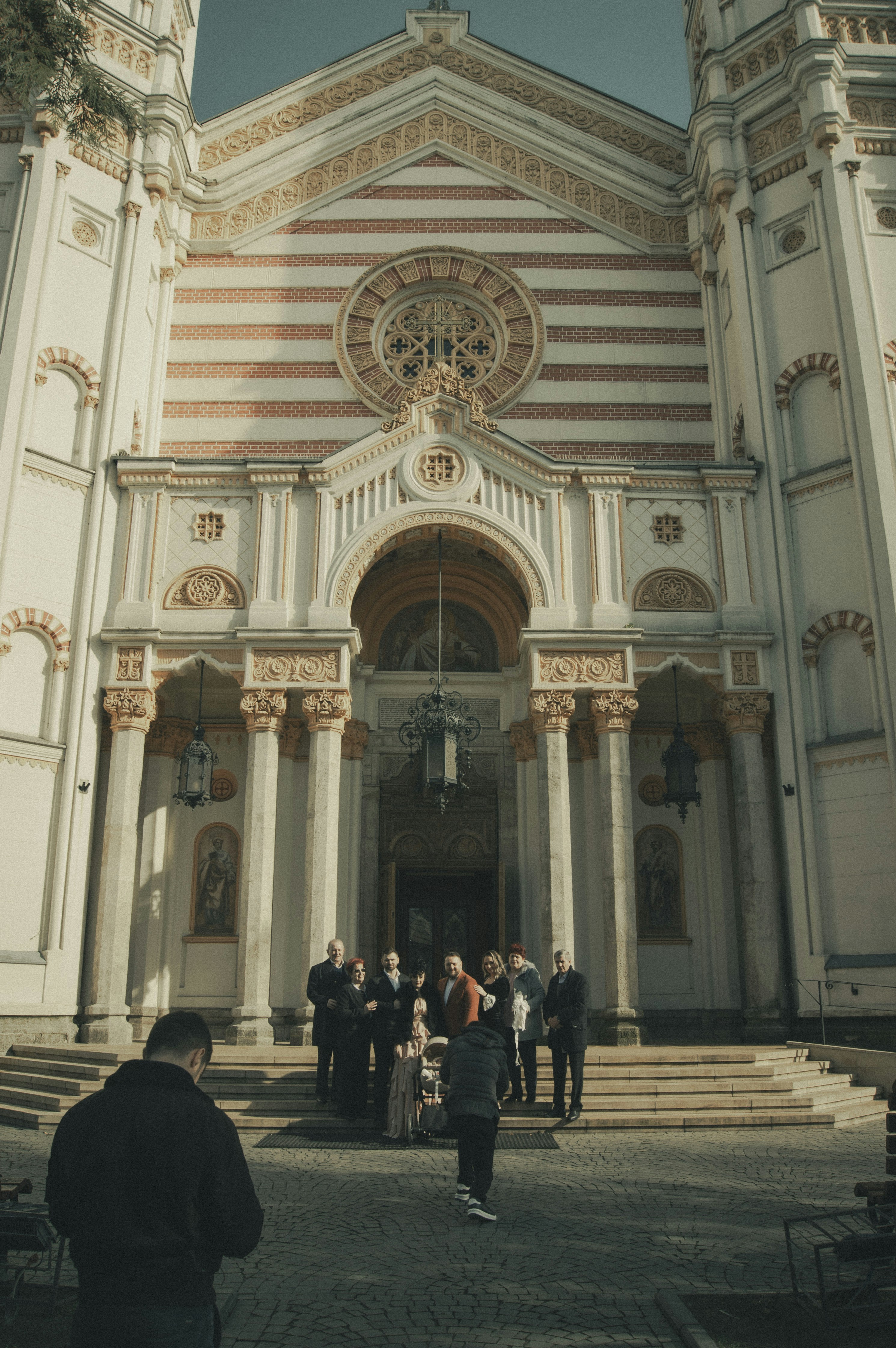 Ceremonial gathering at a grand church entrance framed by ornate arches