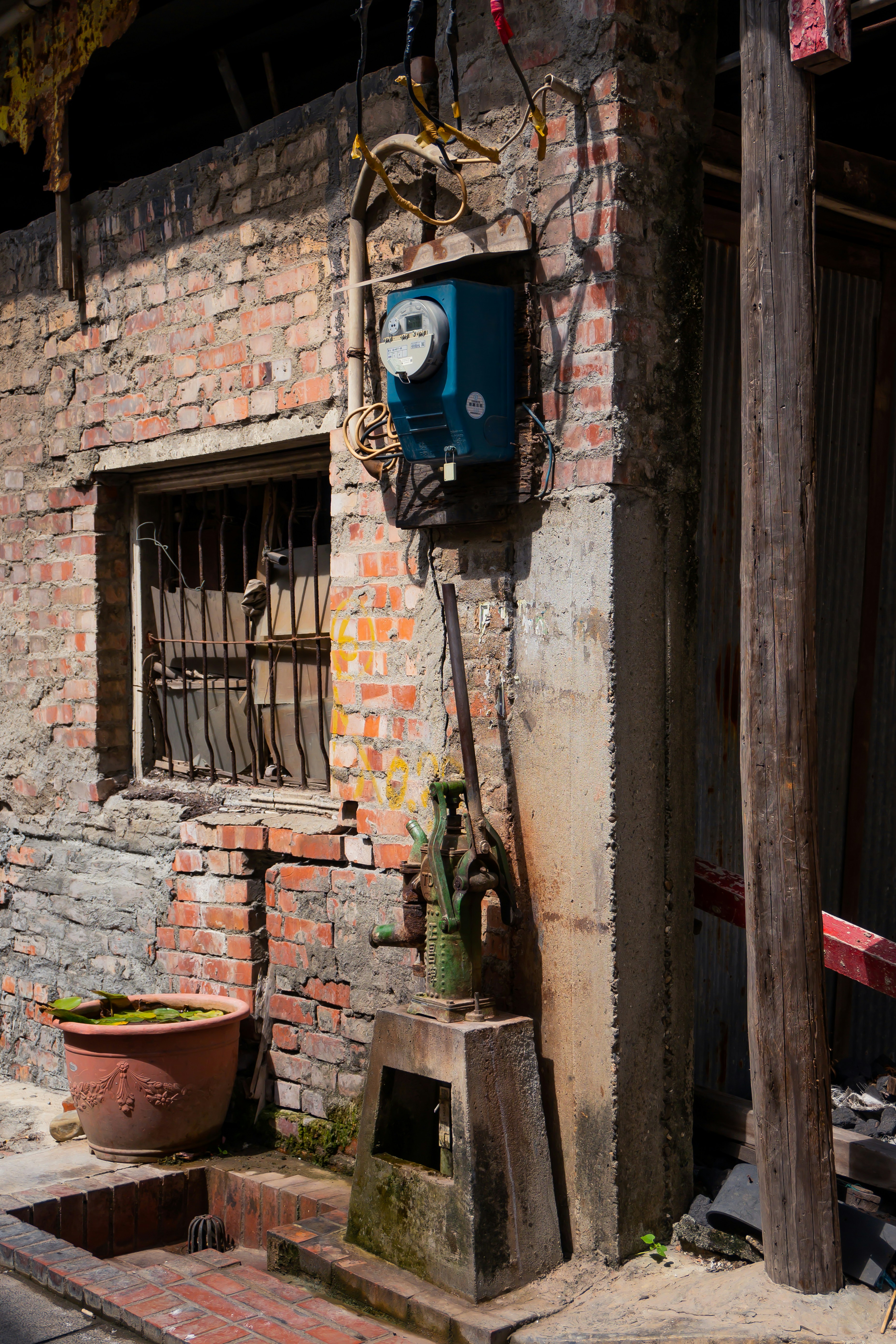 Blue Meter Box on Weathered Brick Wall: A Quiet Street Corner