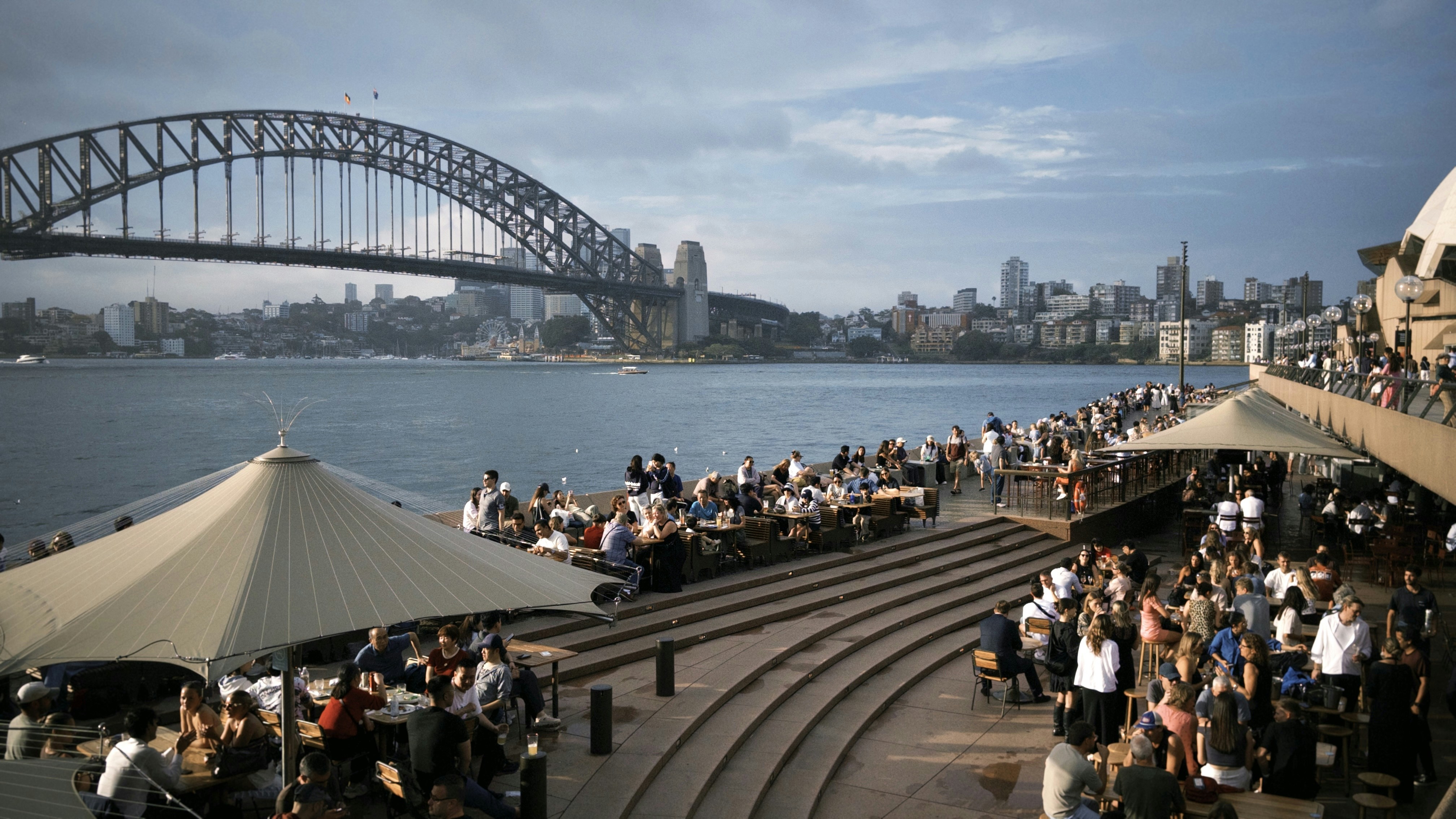 Crowded waterfront promenade under Sydney–Harbour Bridge