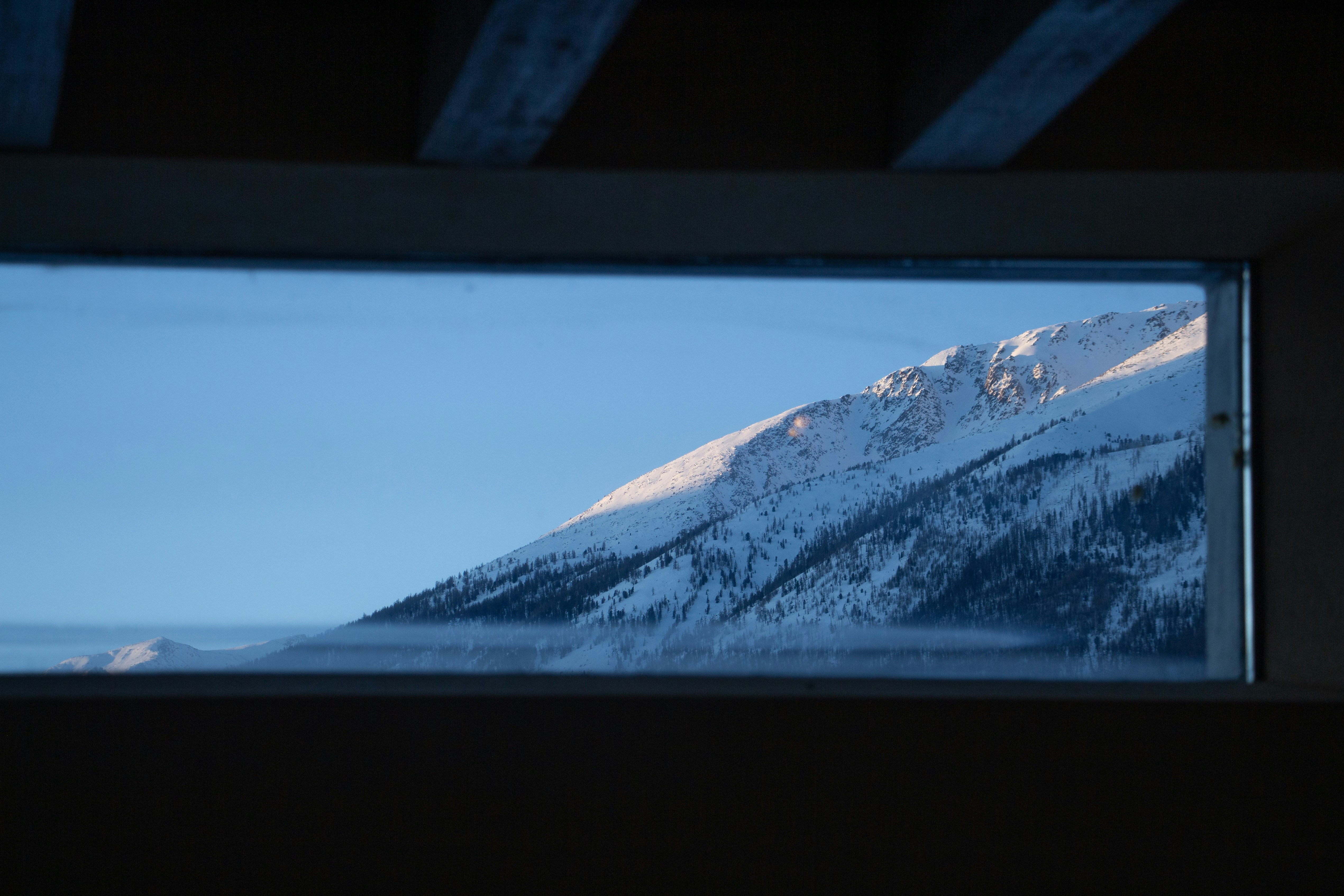 A Quiet Snow-Capped Ridge Through a Framed Window