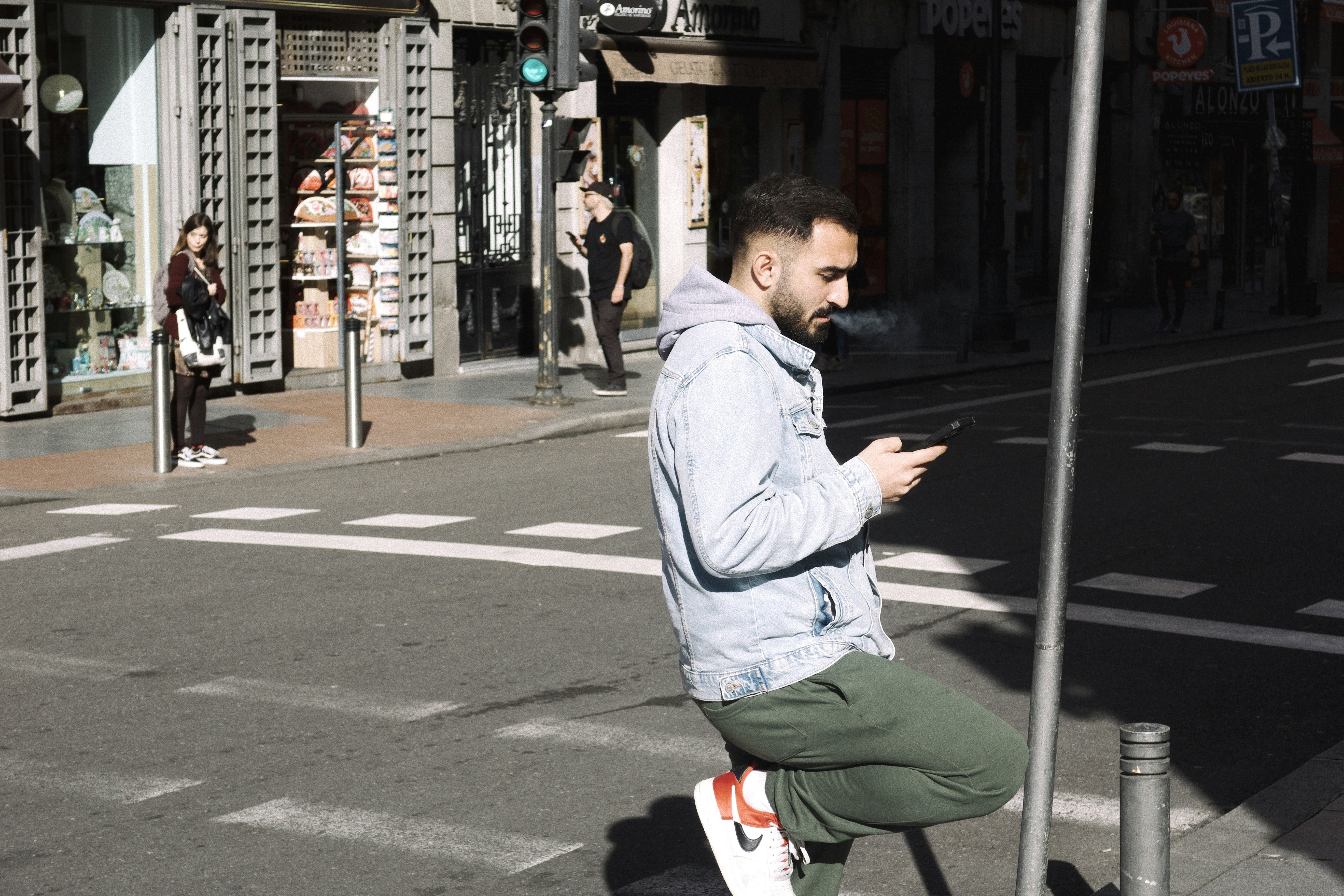Urban moment: a man focused on his phone while seated at the curb
