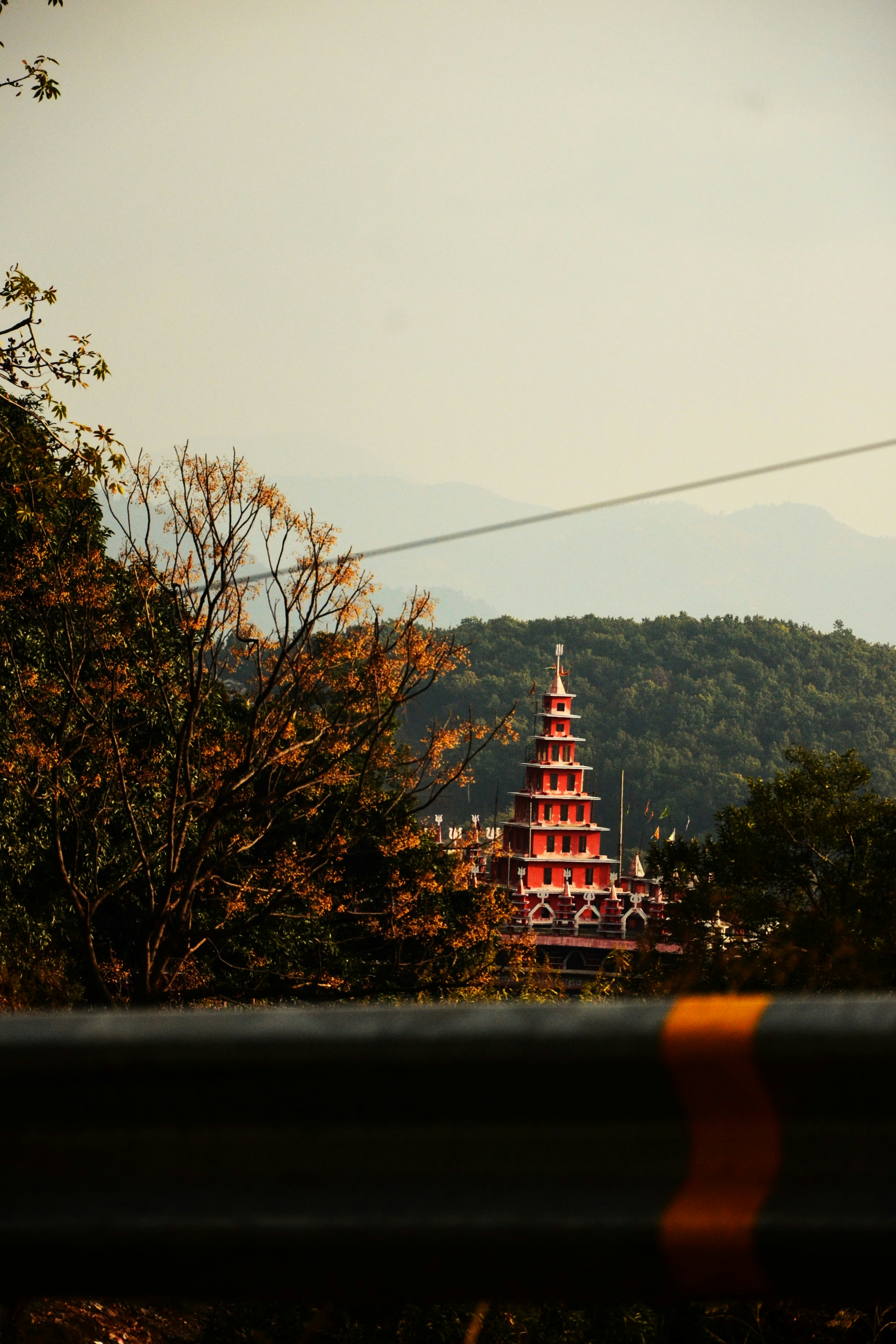 Red Pagoda Emerges Beyond Autumn Canopy on a Distant Ridge