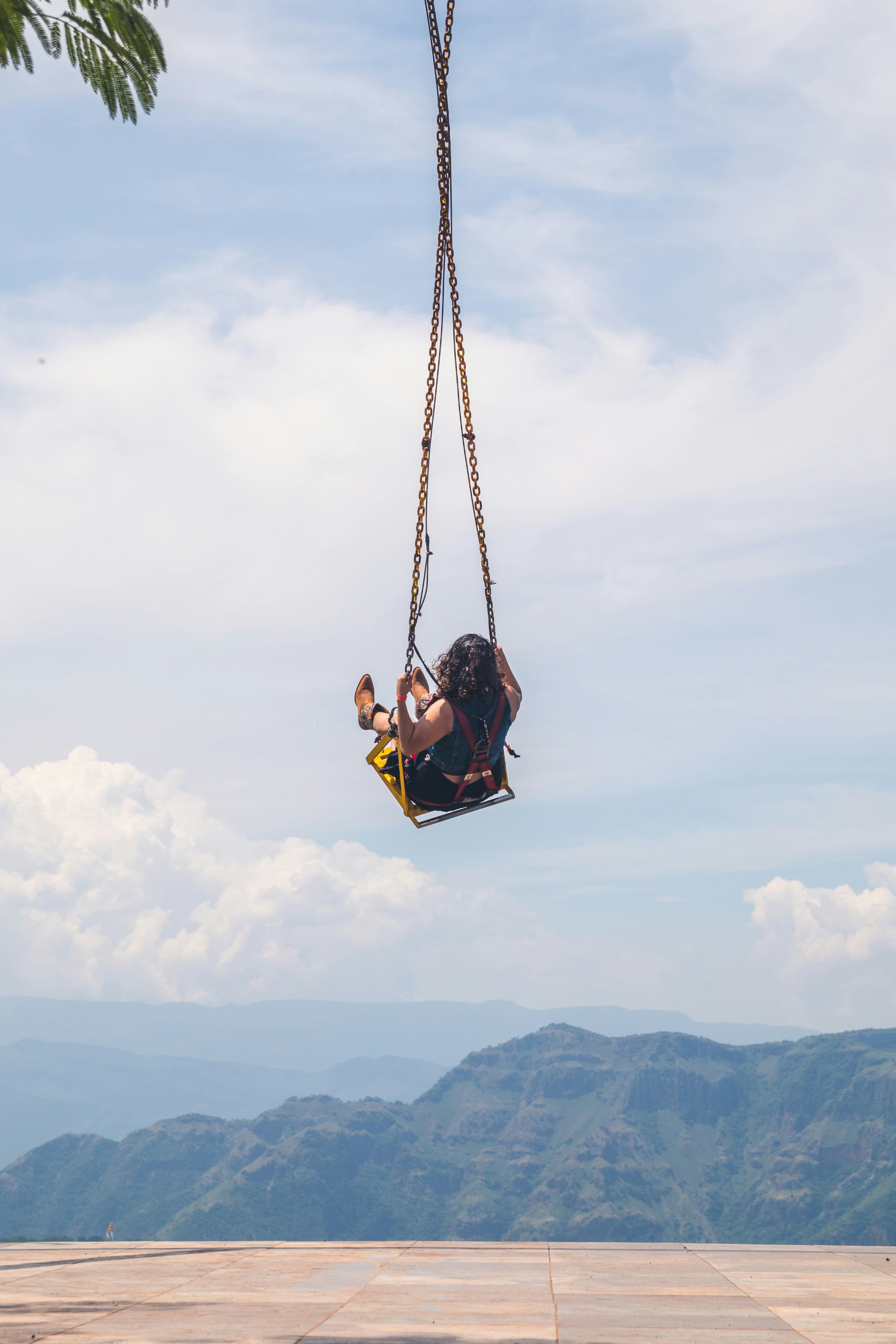 Swinging Over the Horizon: A Child on a Mountain Swing Against a Vast Sky