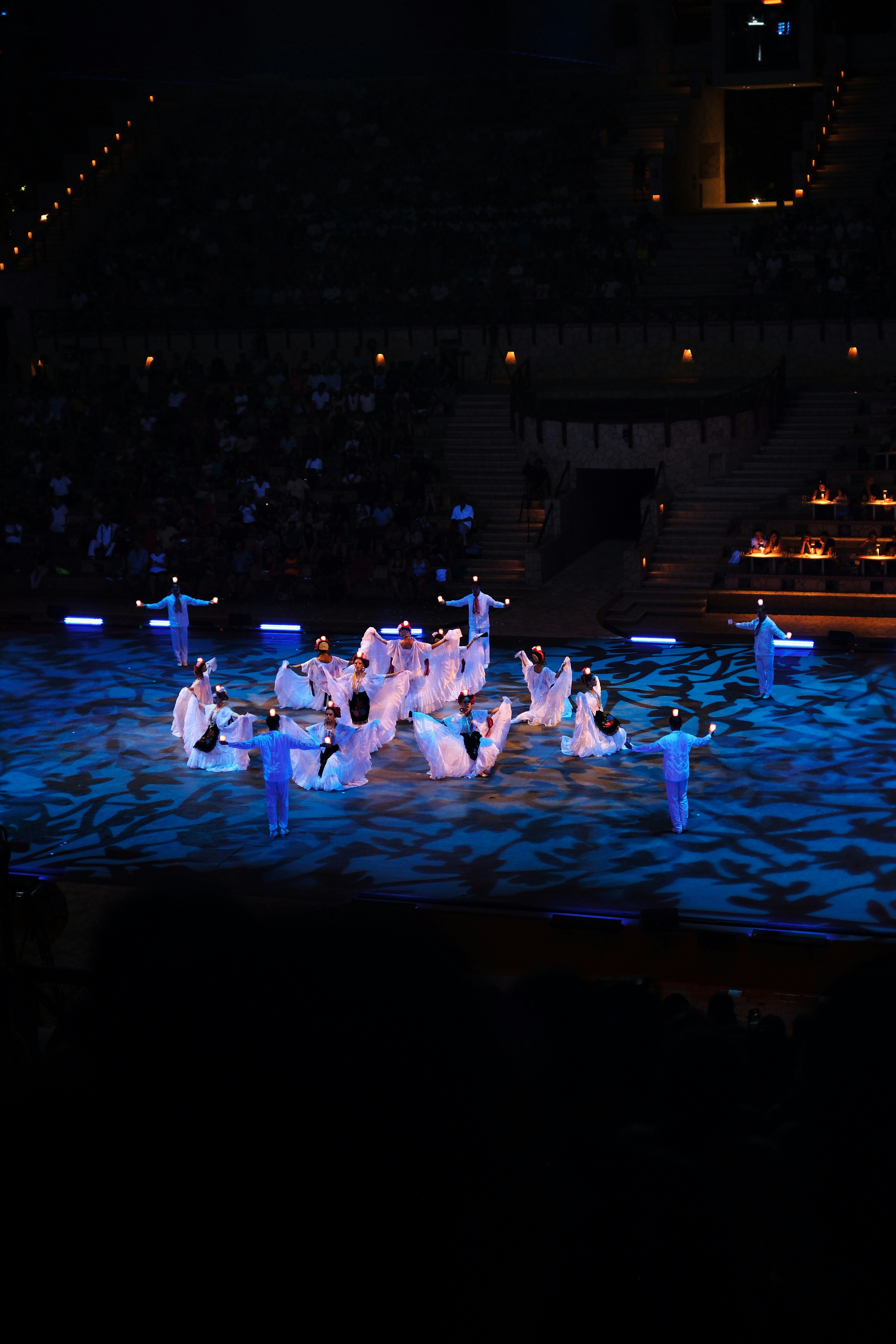 Blue-lit Choir of Dancers: A Circular Stage Beneath the Arena Lights