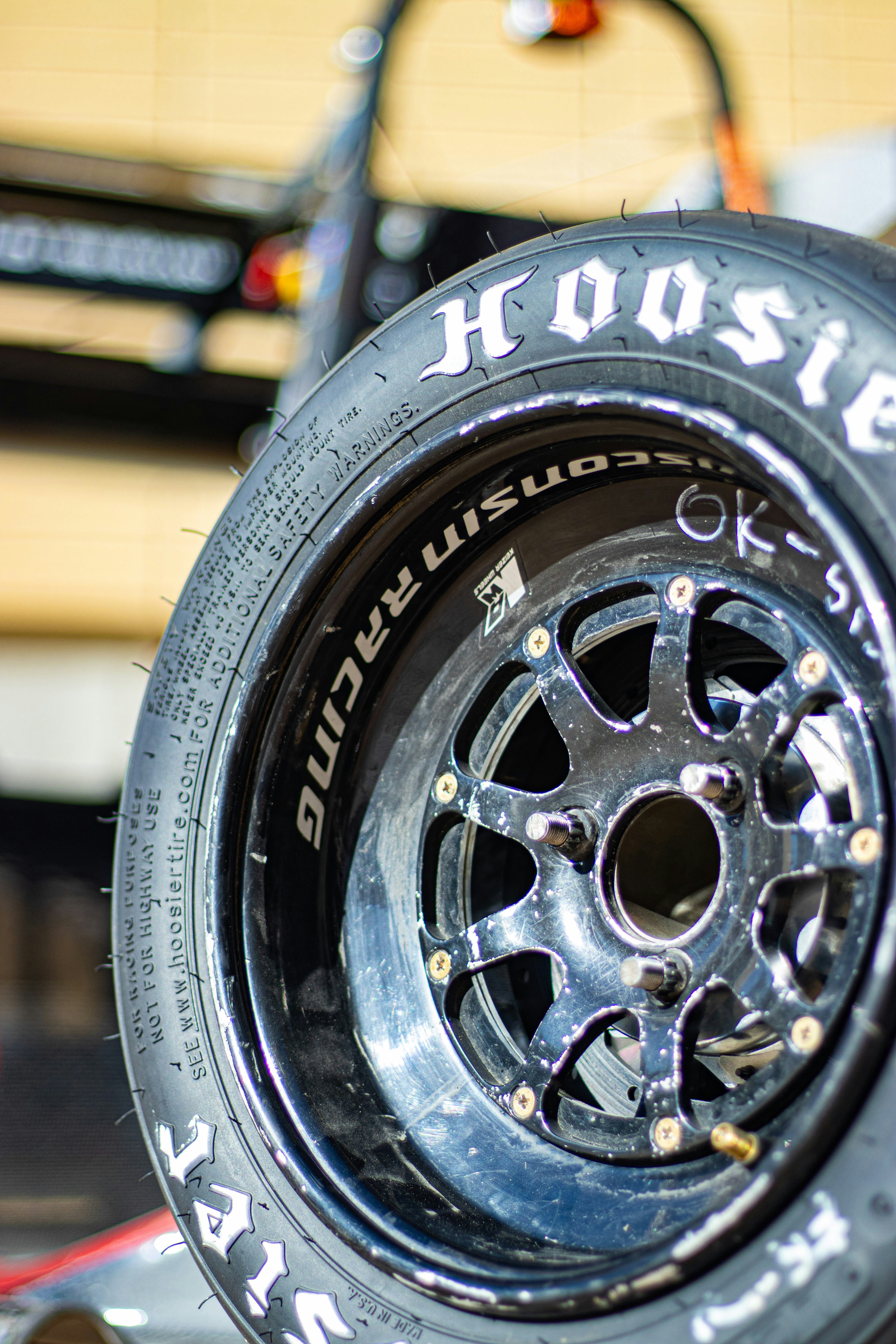 Tire close-up: a glossy racing wheel under workshop lights