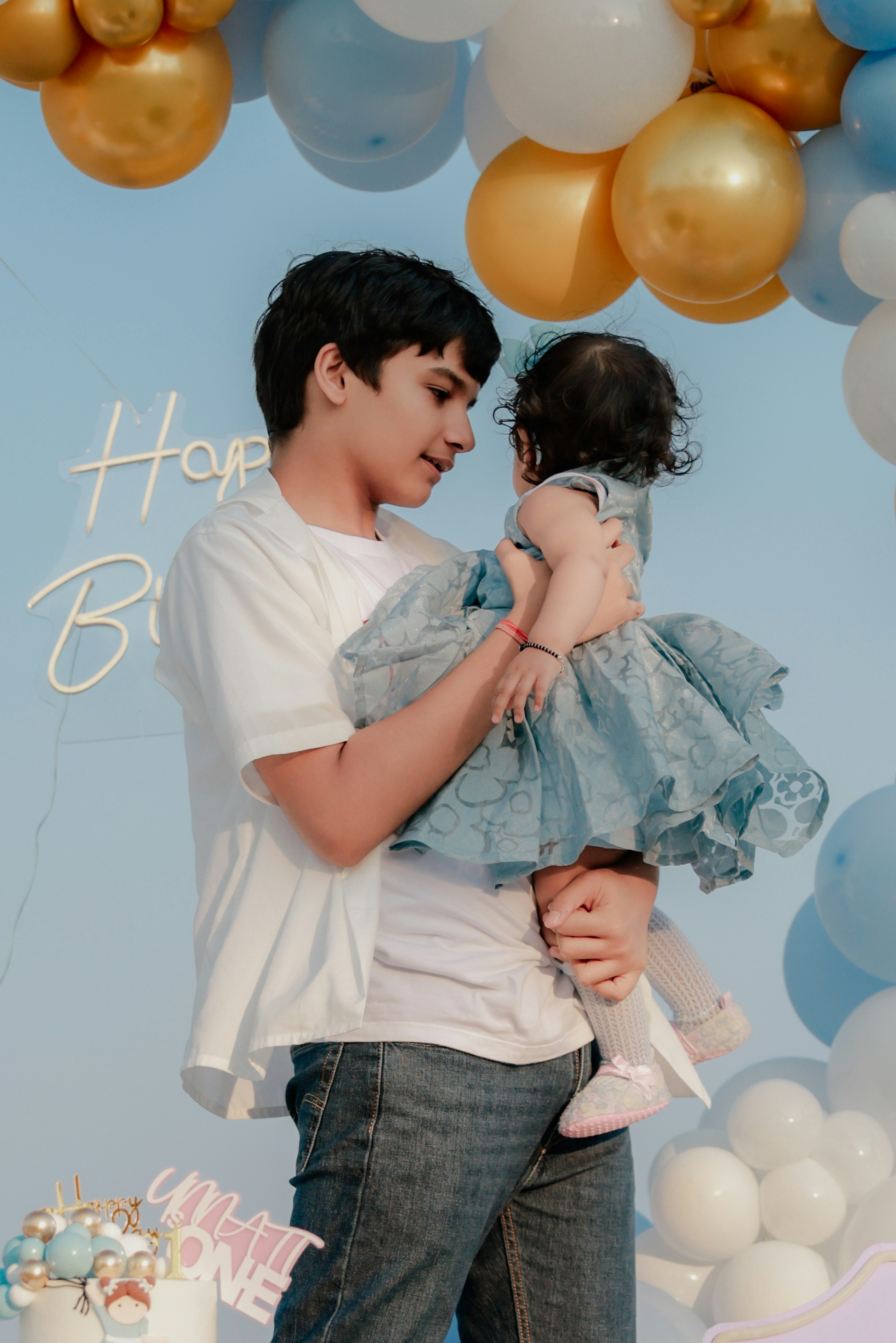 Father’s gentle embrace under a pastel balloon arch