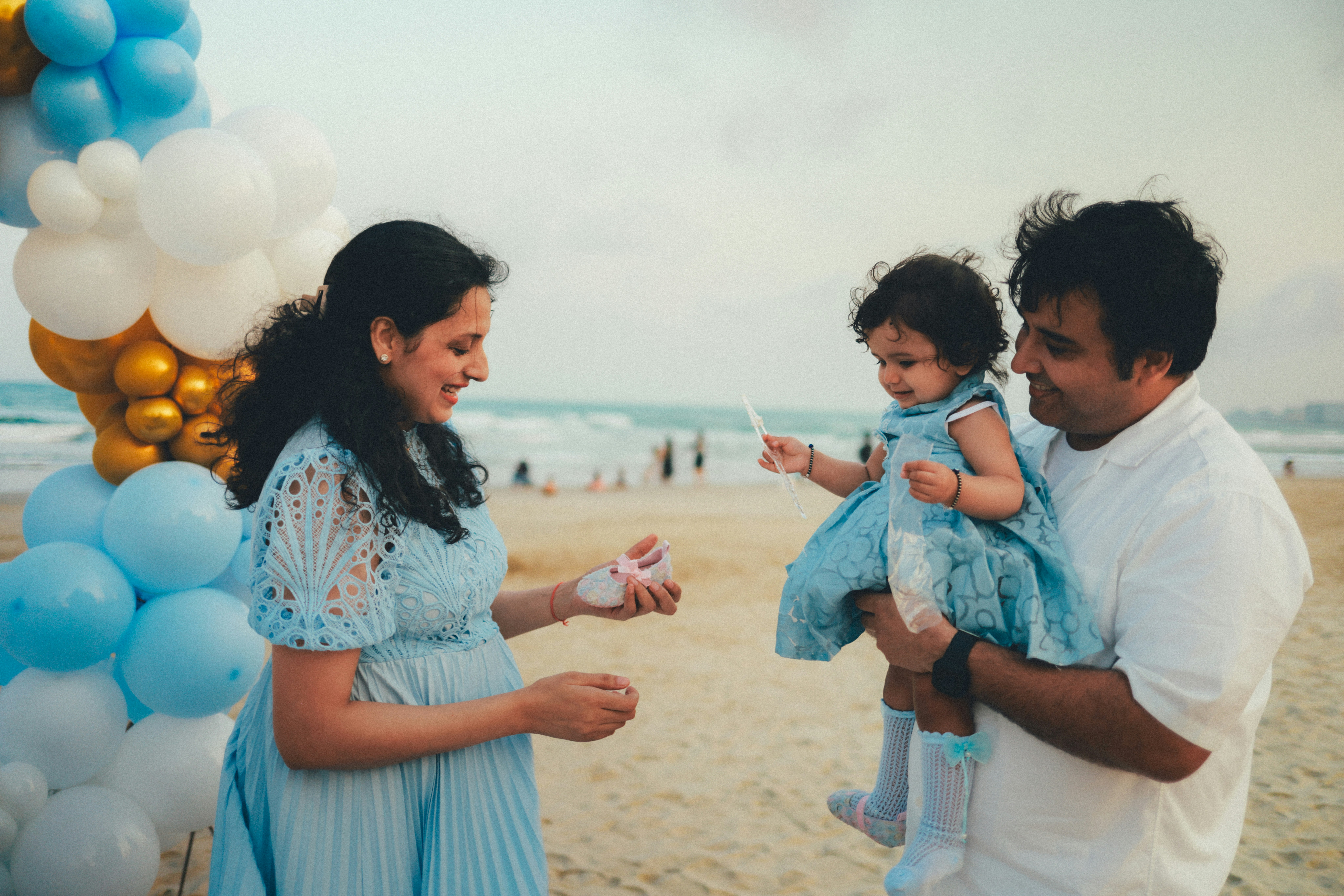 Blue dresses and birthday balloons on a sunlit beach celebration
