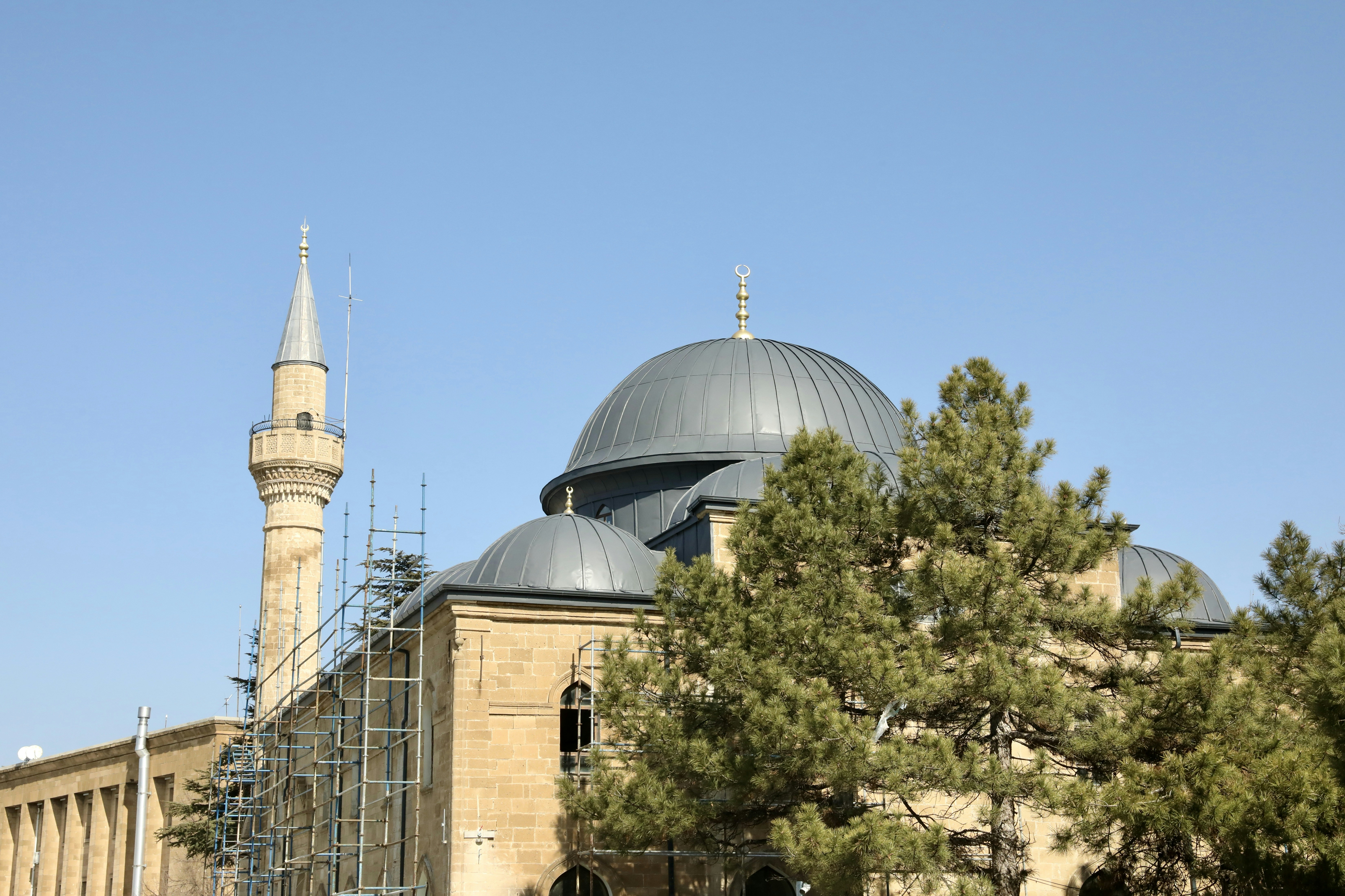 Domed Center: A Mosque Under Construction with Scaffolding and Trees