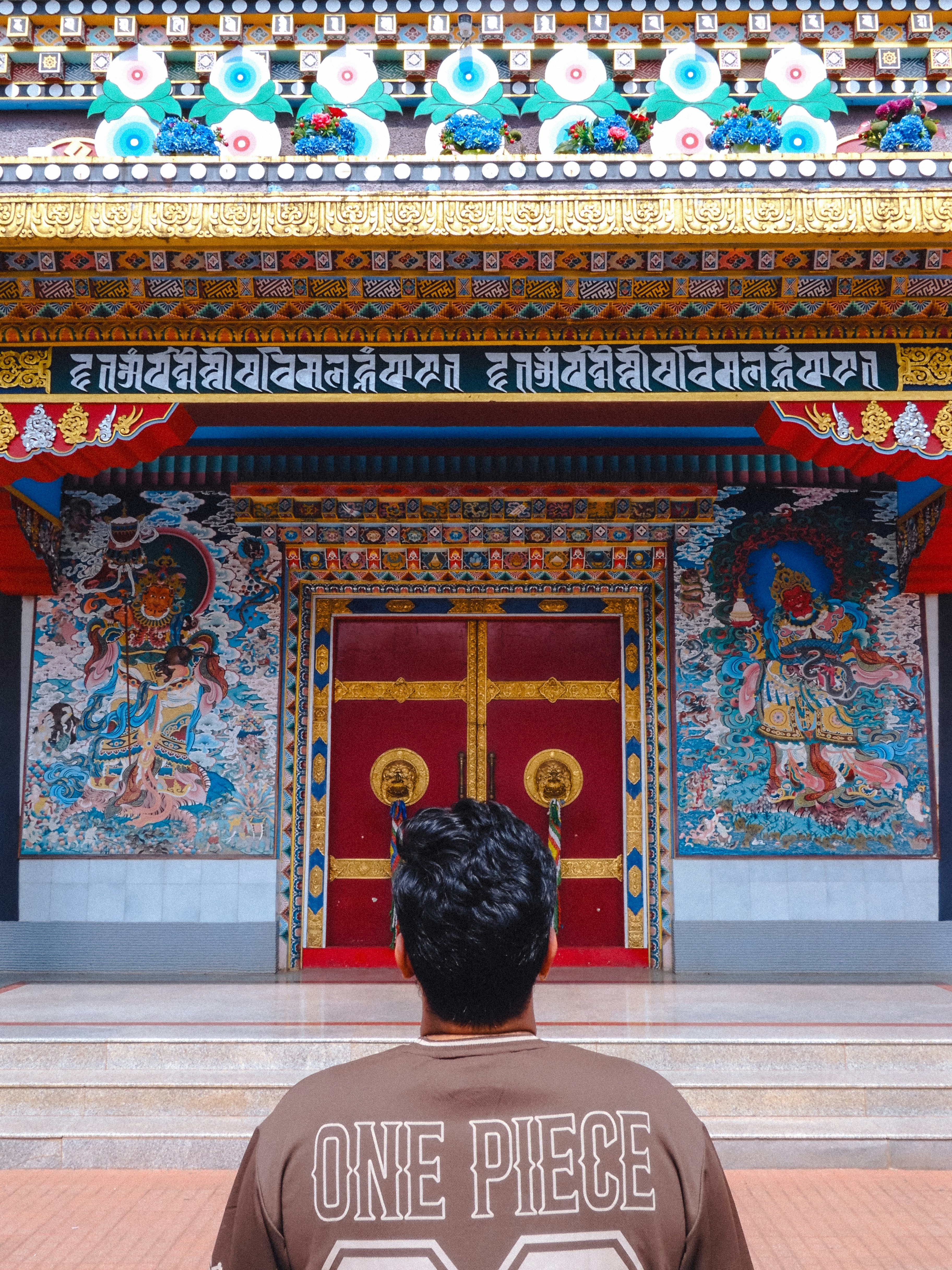 Man in front of a colorful tibetan temple entrance