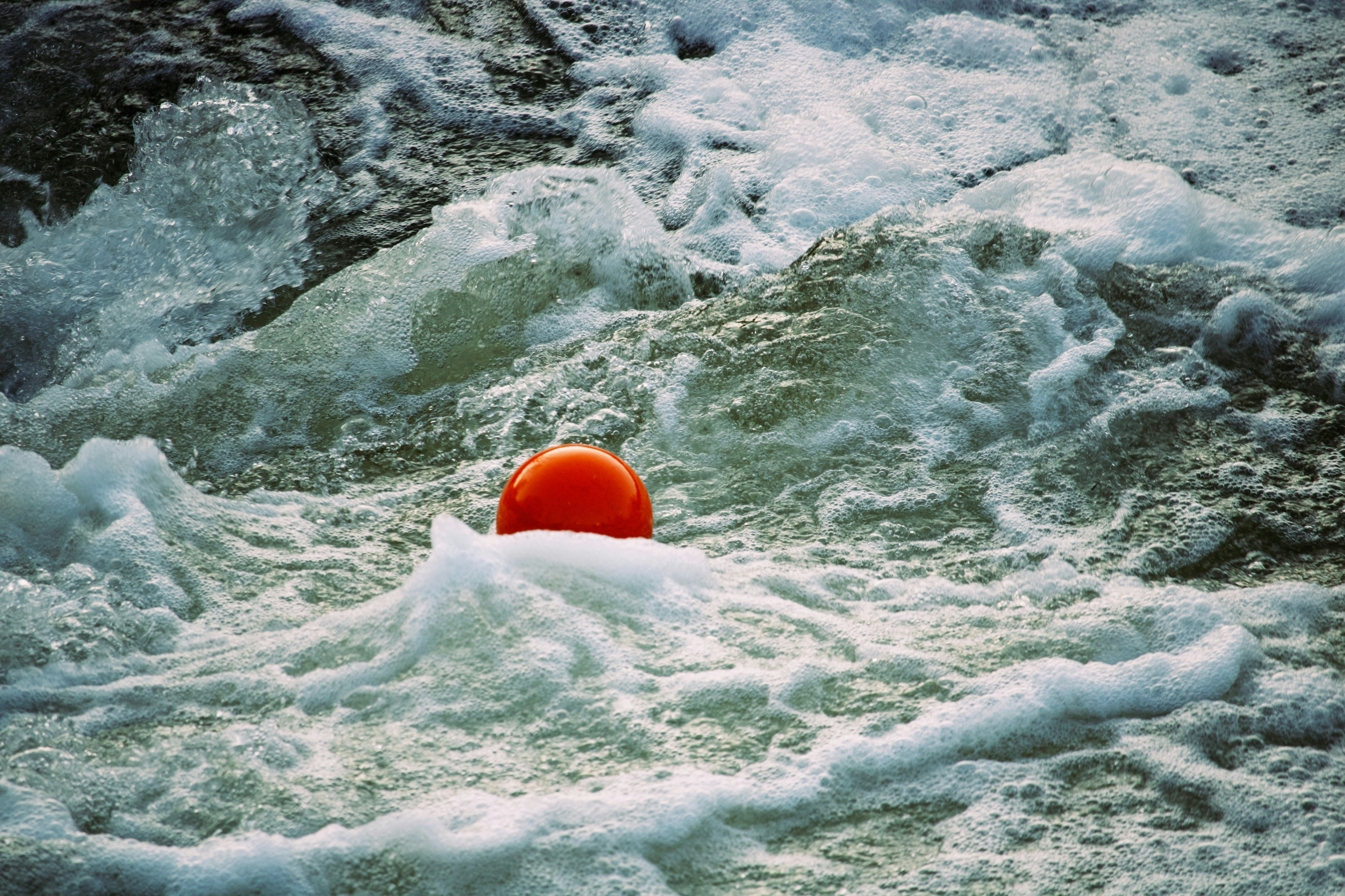 Red Buoy Surrounded by White Crest in Turbulent Waters