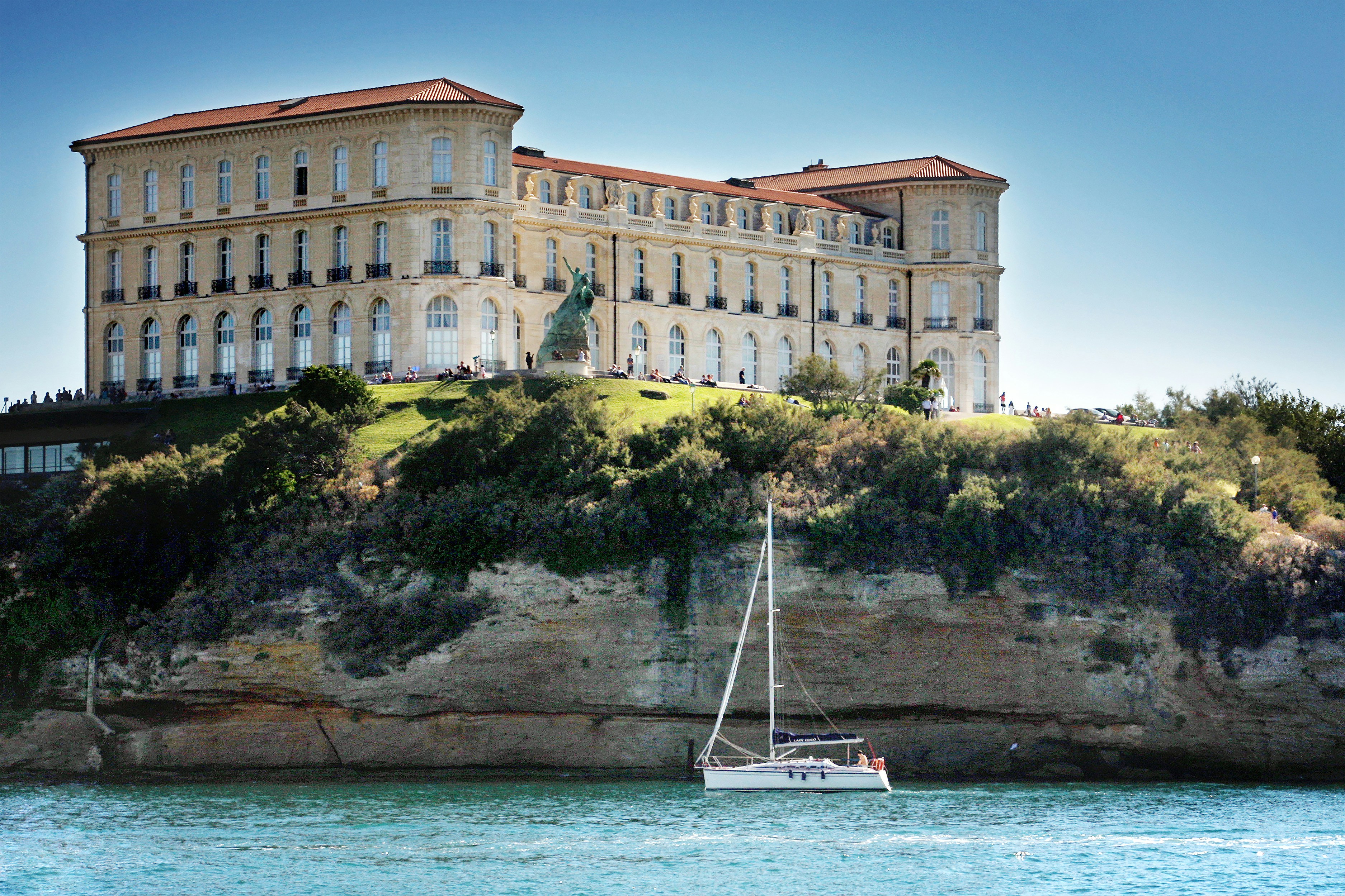 Hilltop Castle Overlooking a Sailboat on turquoise Waters