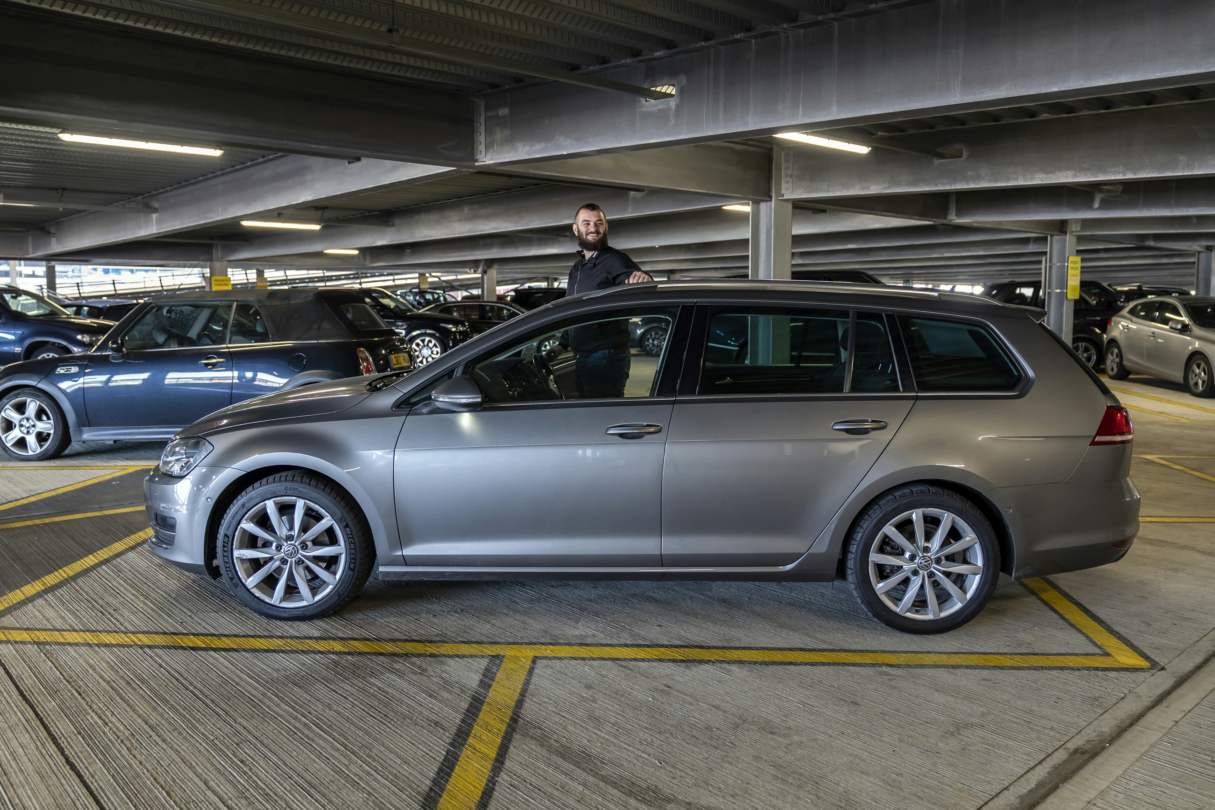 Silver Station Wagon in a Dim Parking Garage, a Man Standing Beside