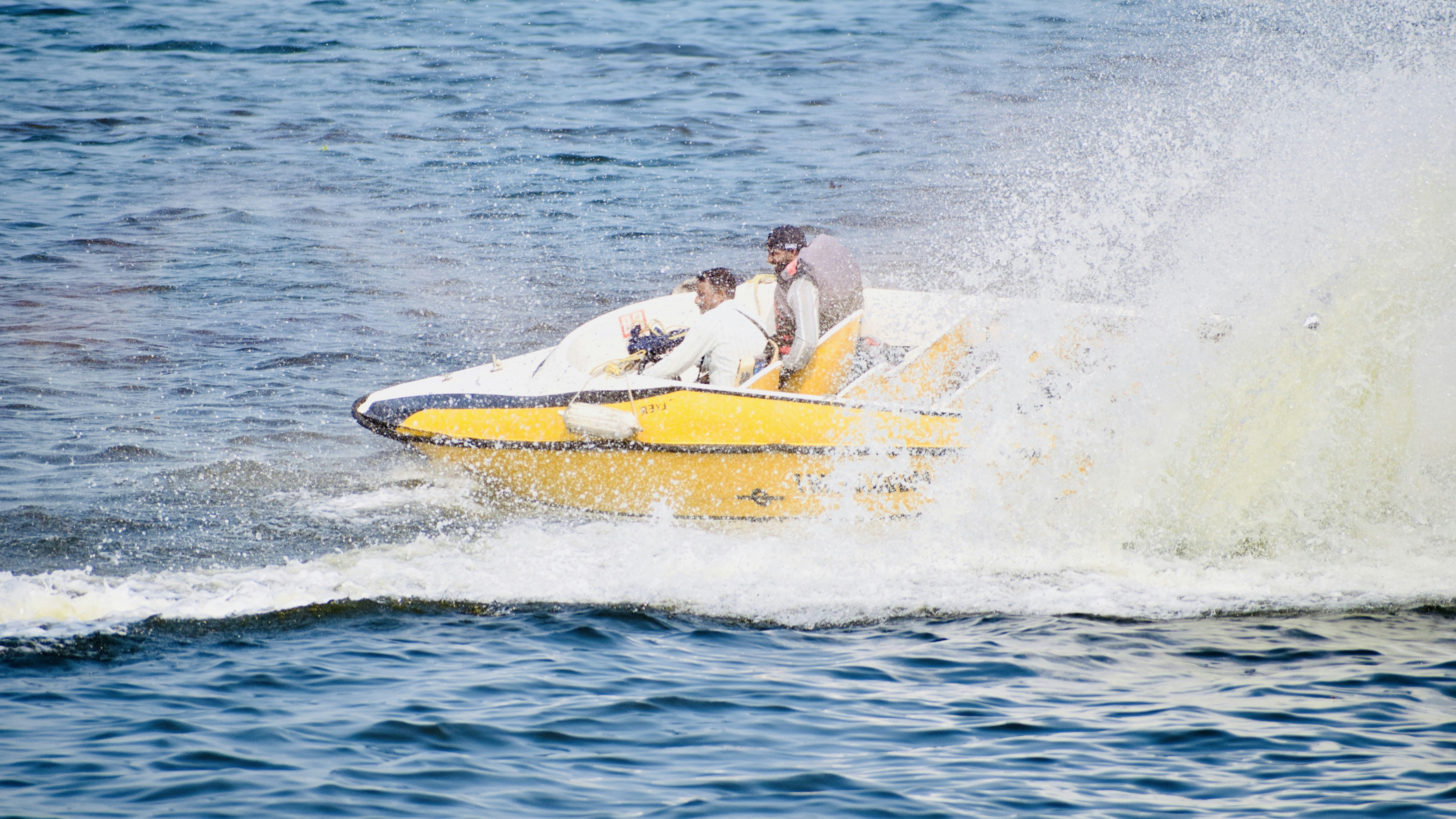 Yellow speedboat erupts in a salted spray across the sea