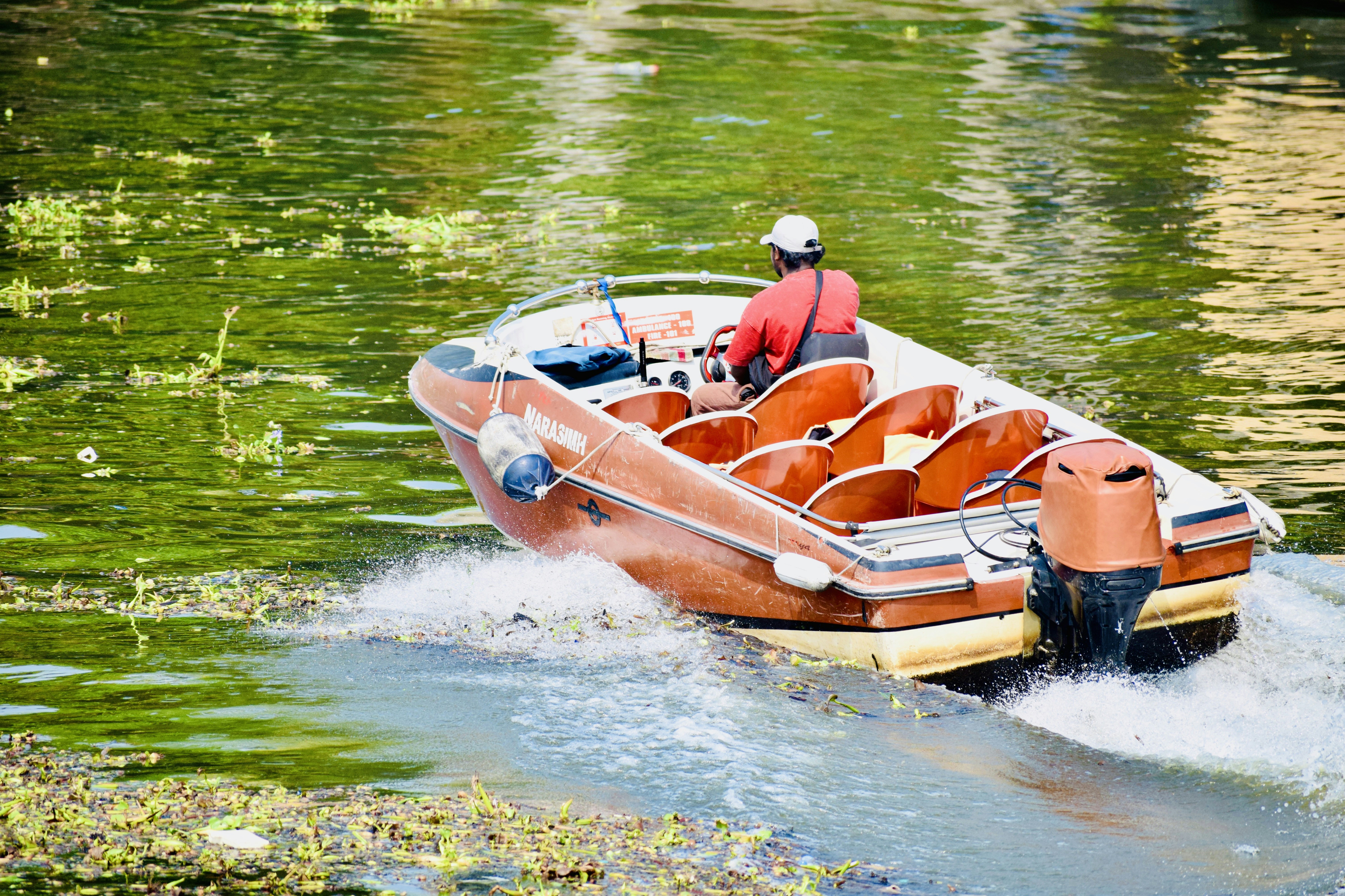 Red Outboard Ferry Skims a Green-Reflective Wake