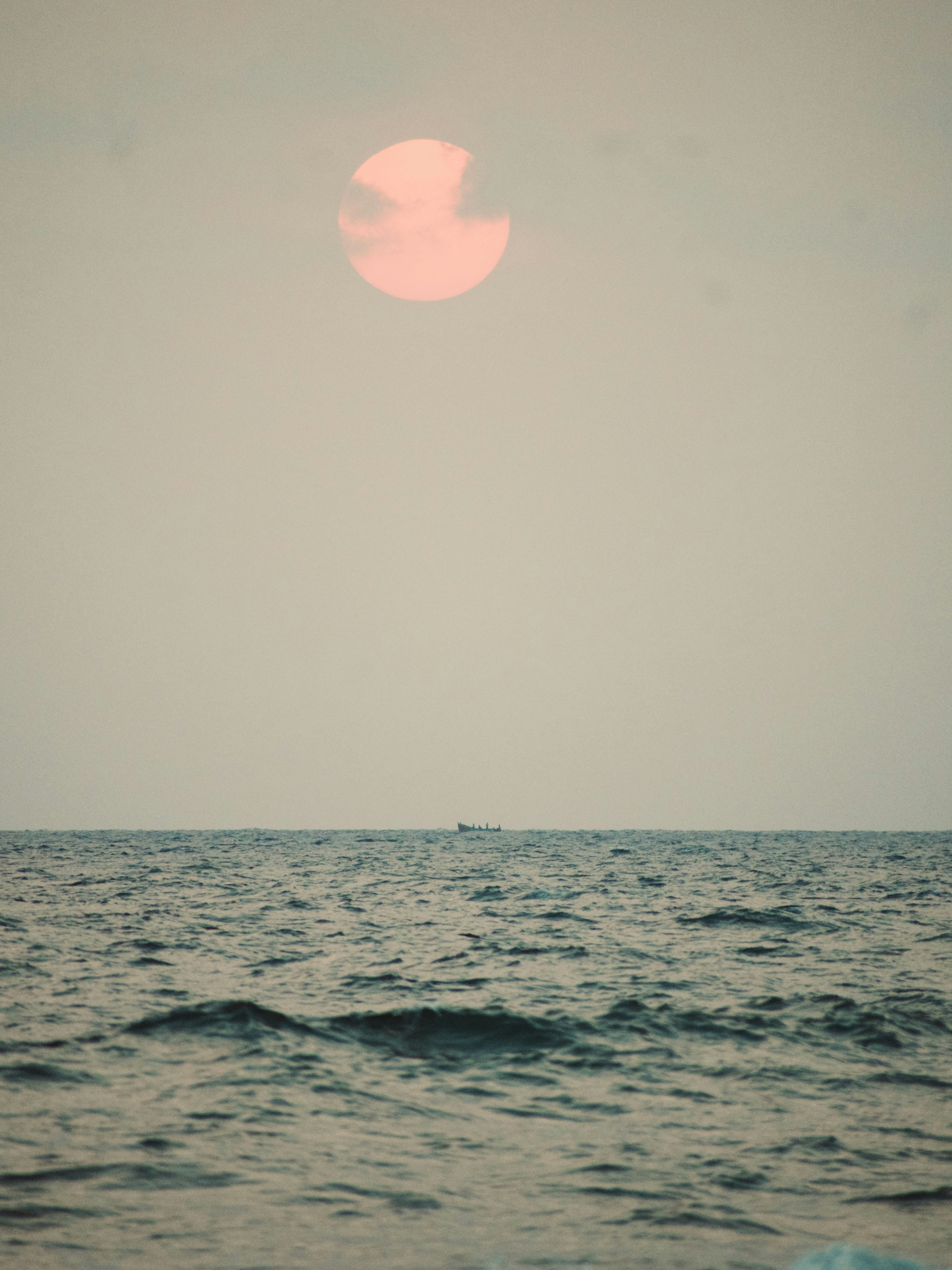 Muted Horizon: The Sun Dips Over Quiet Seas