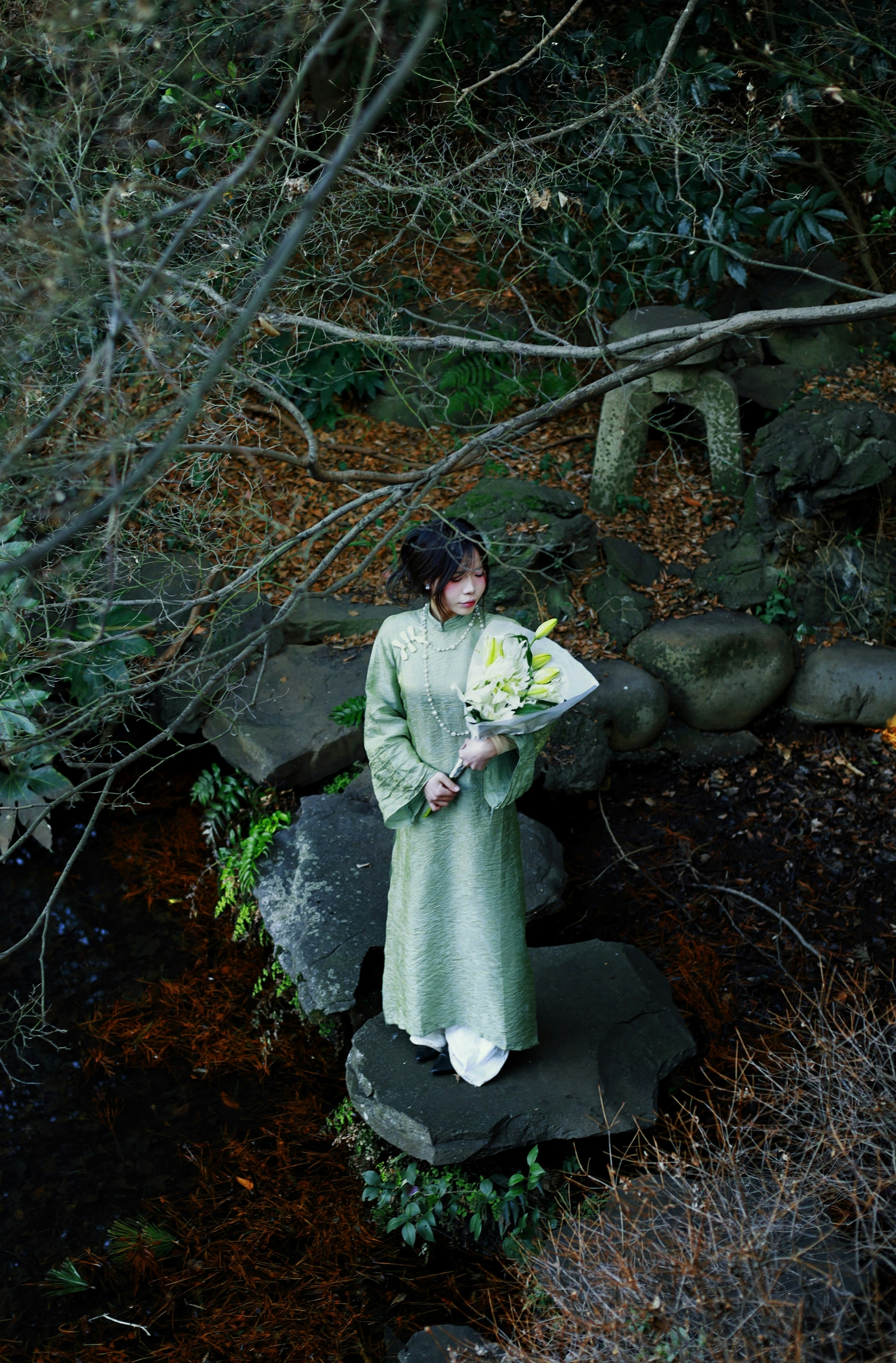 Elegy in Green: A Woman with White Bouquet Amid Stone and Fern