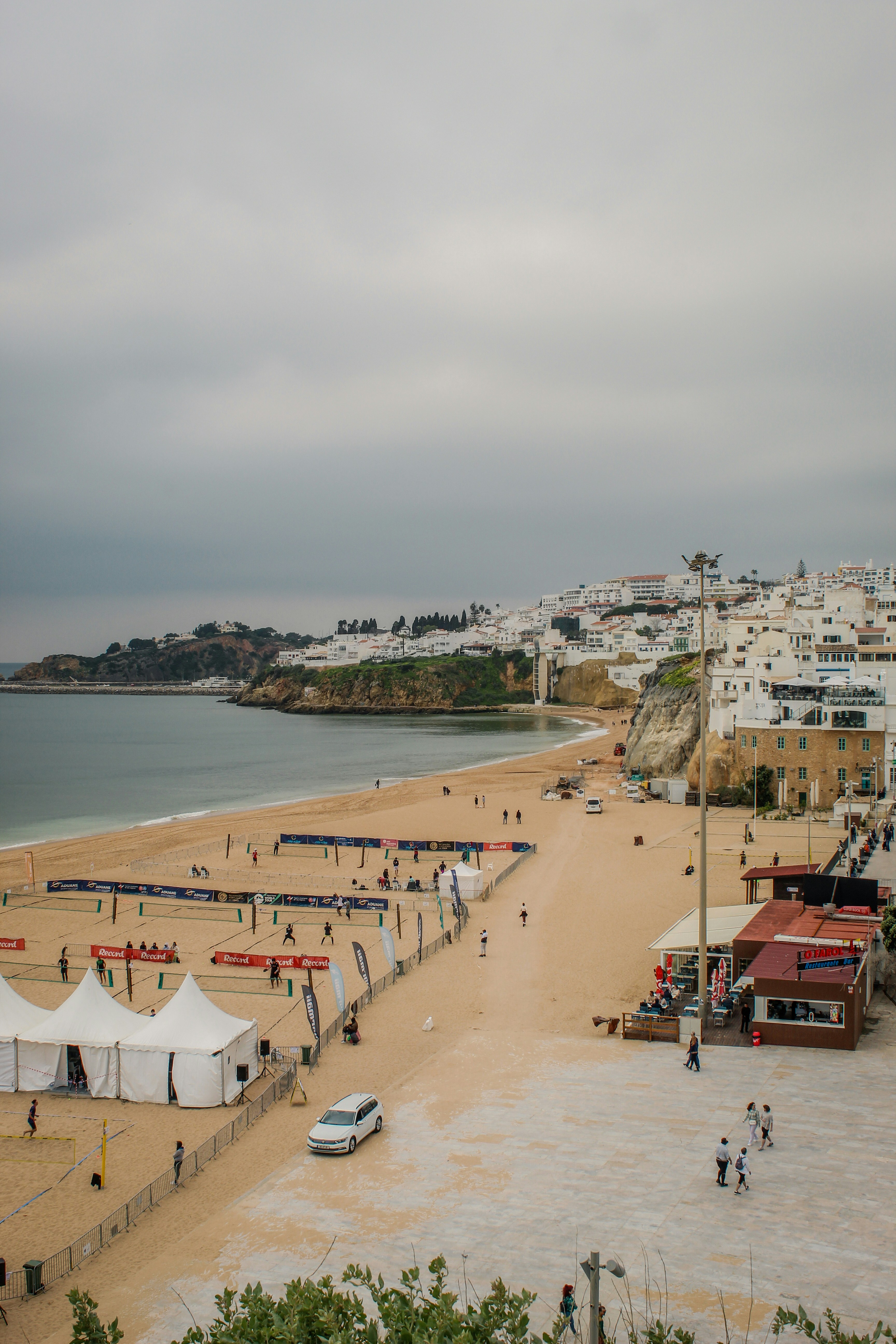 Coastal Promenade: Beachgoers and Whitewashed Cliffs Under a Grey Horizon