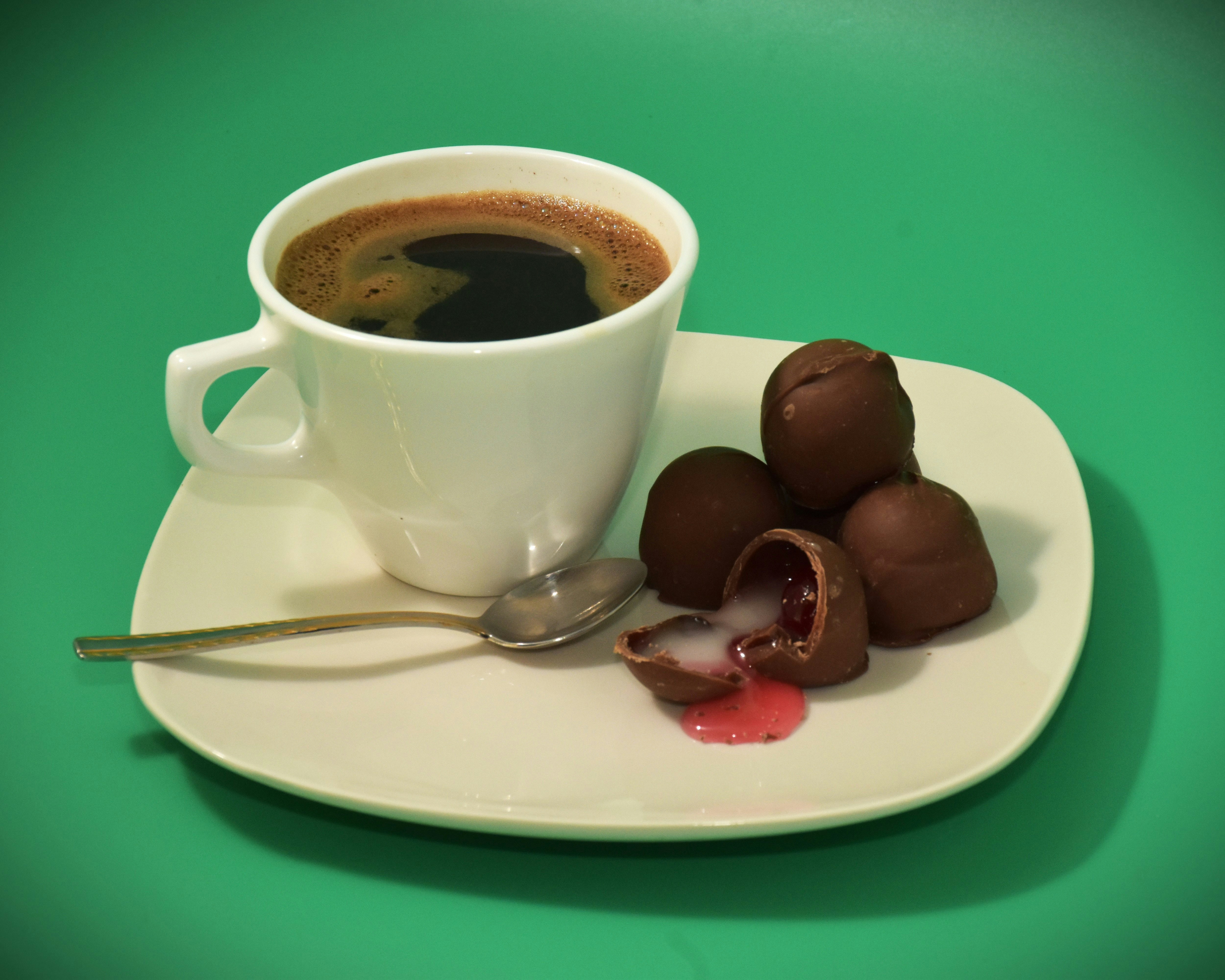 Cup of Contrast: Dark Coffee and Sweet Chocolates on a Bright Plate