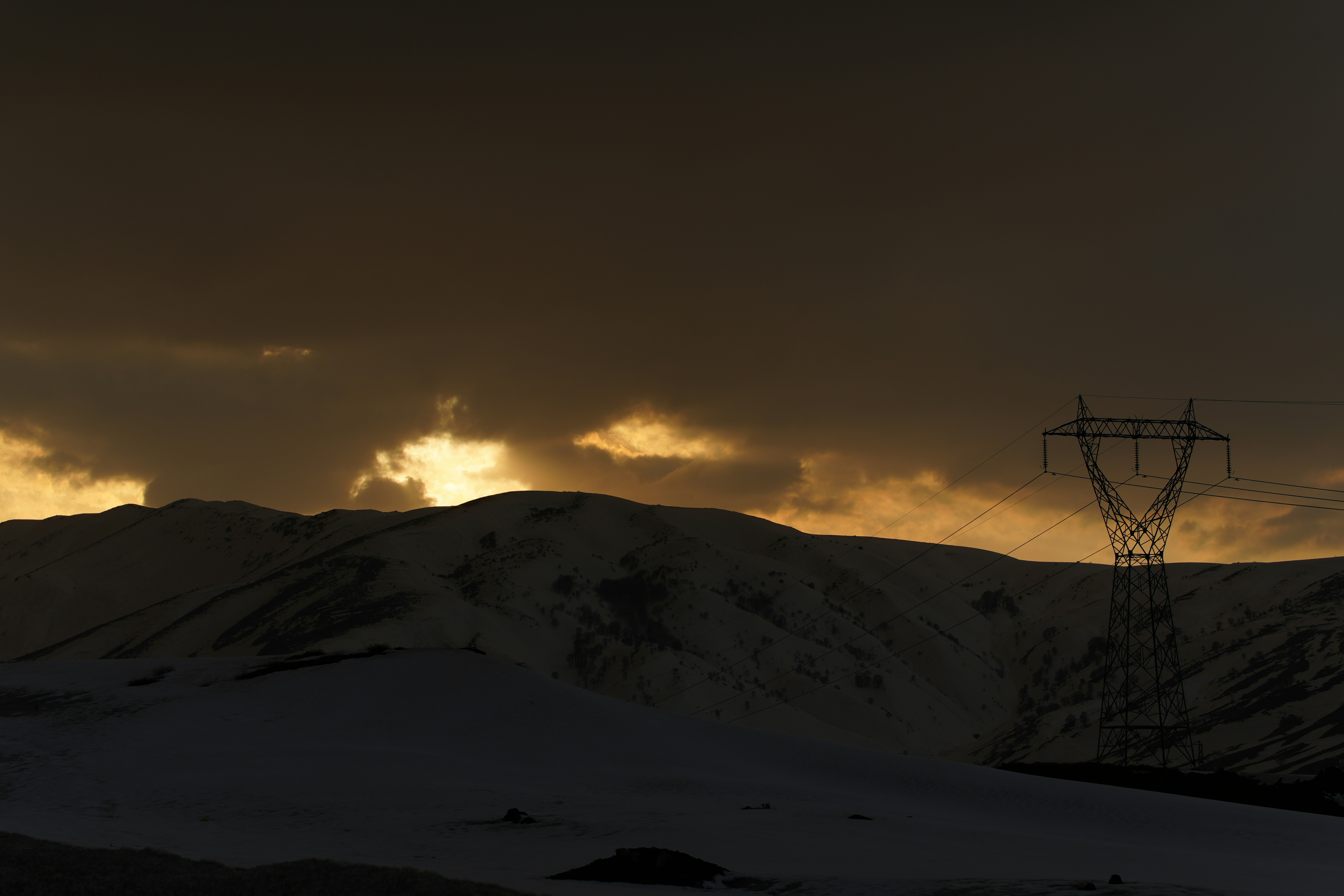 Low-sun Silence Over Snowy Ridges with Powerline Silhouette