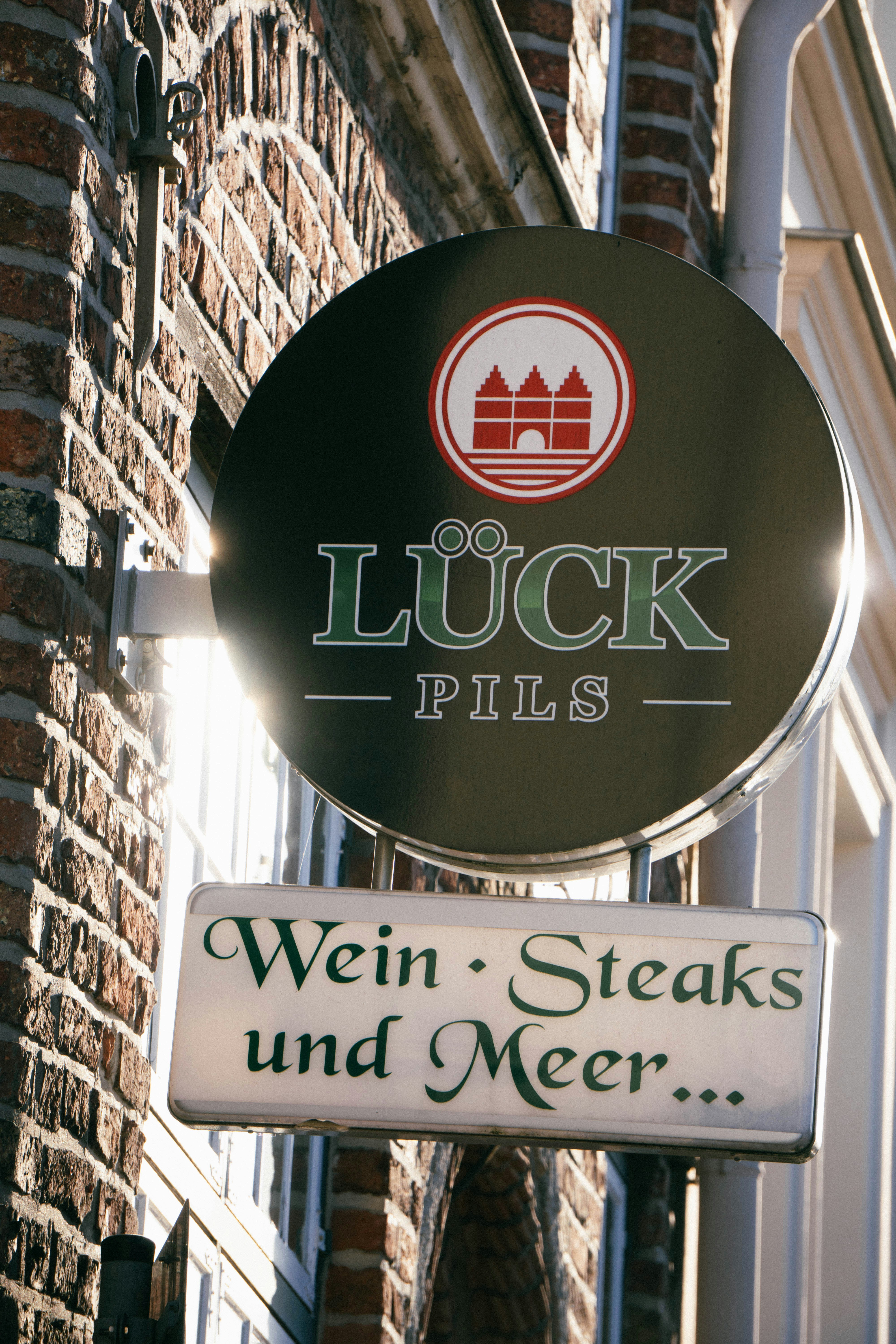 Lück Sign: A Round Green Beacon Above a White-Paneled Biergarten
