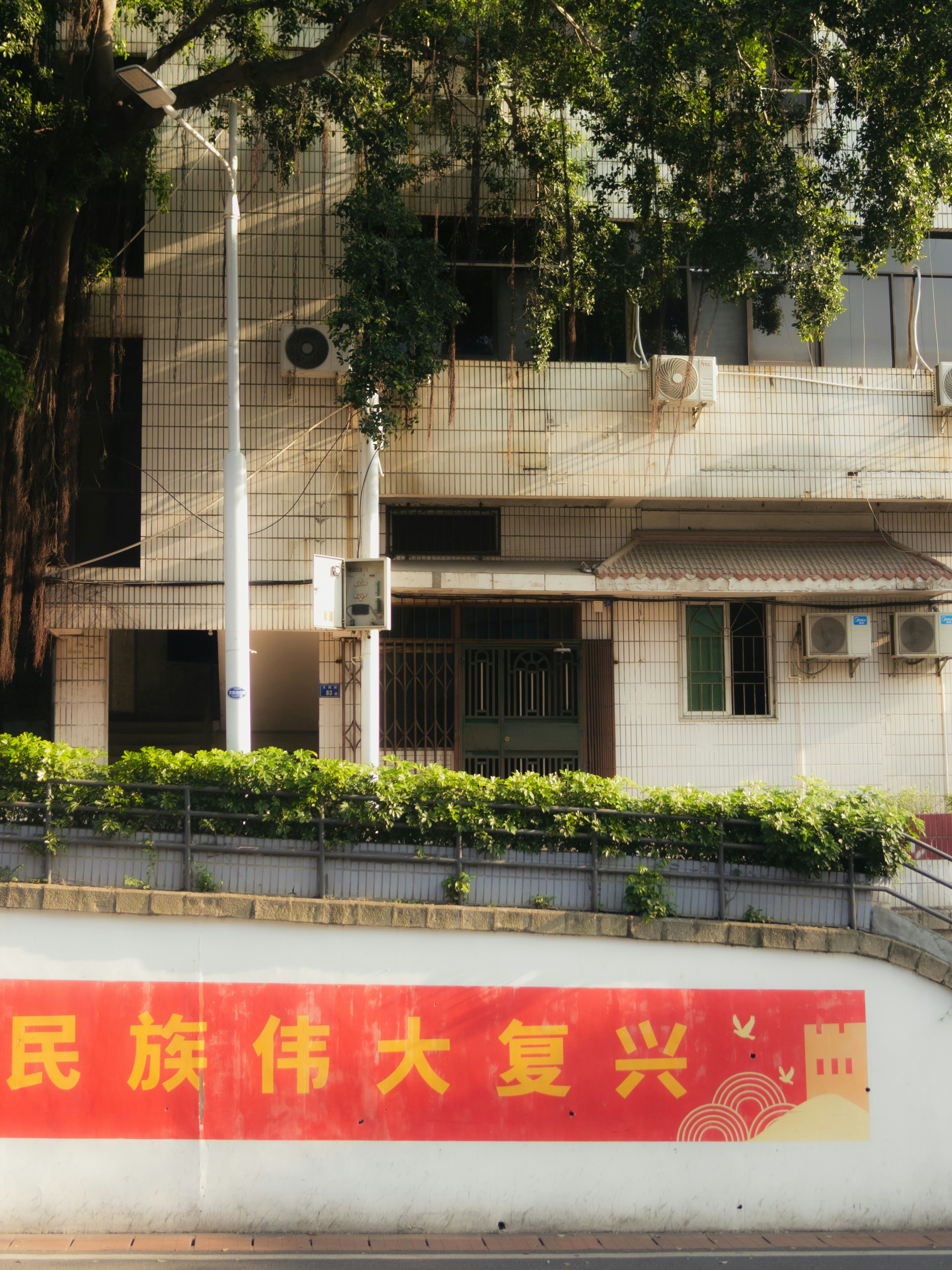 Building with red banner and lush green tree