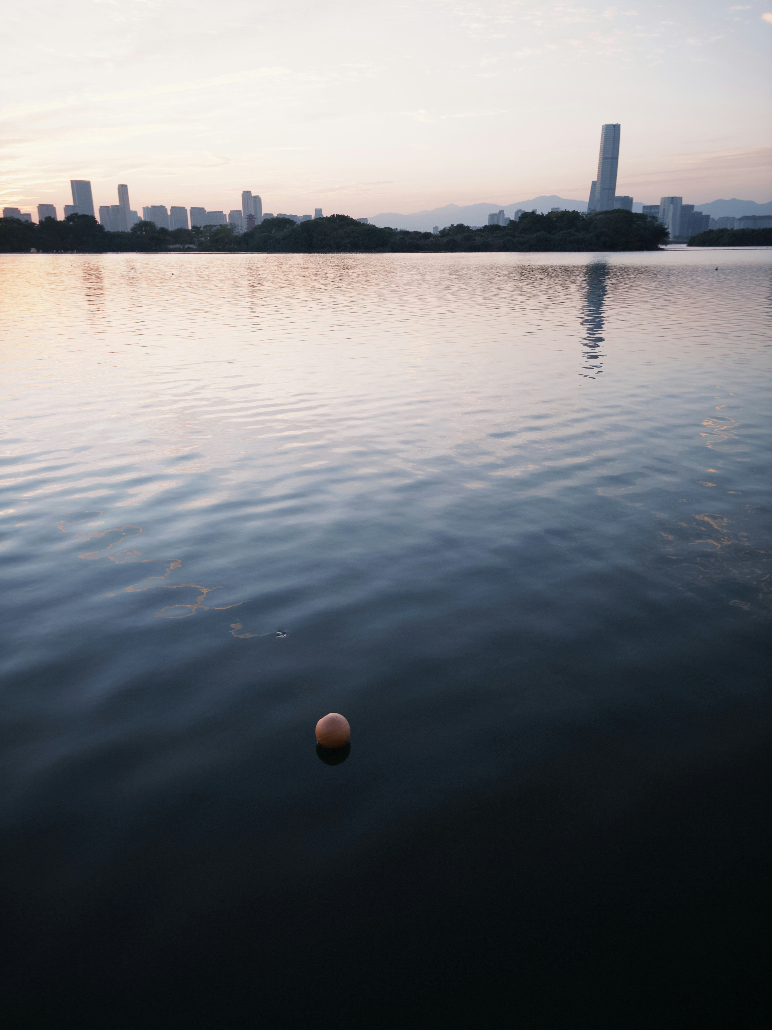 Calm Horizon: Sunset City Silhouette Across Tranquil Water