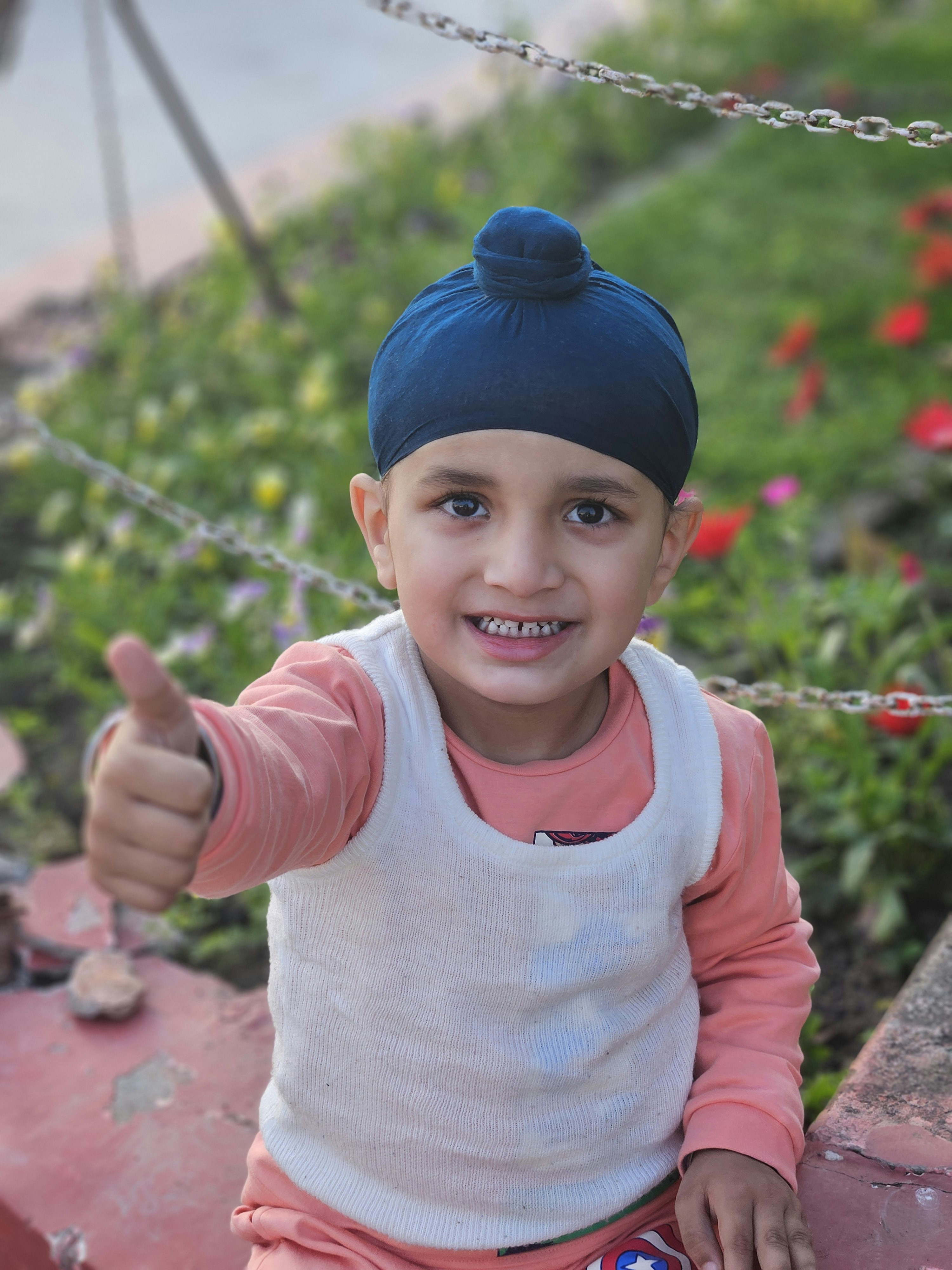 Cheerful thumbs-up: a young student's bold pose in a sunlit garden