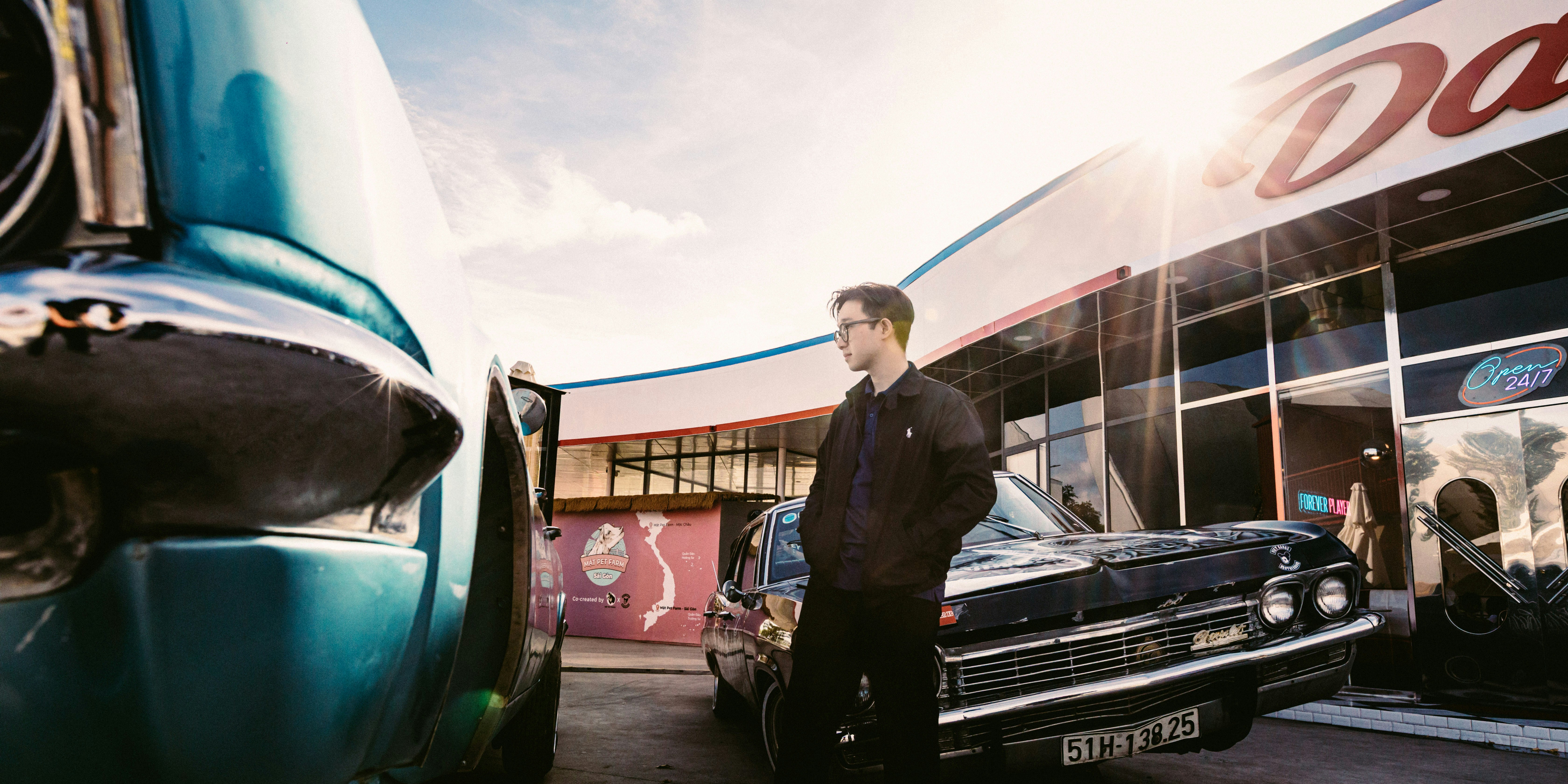 Mid-Century Meet-Up: A shadowed figure by a vintage car at a neon-lit service plaza