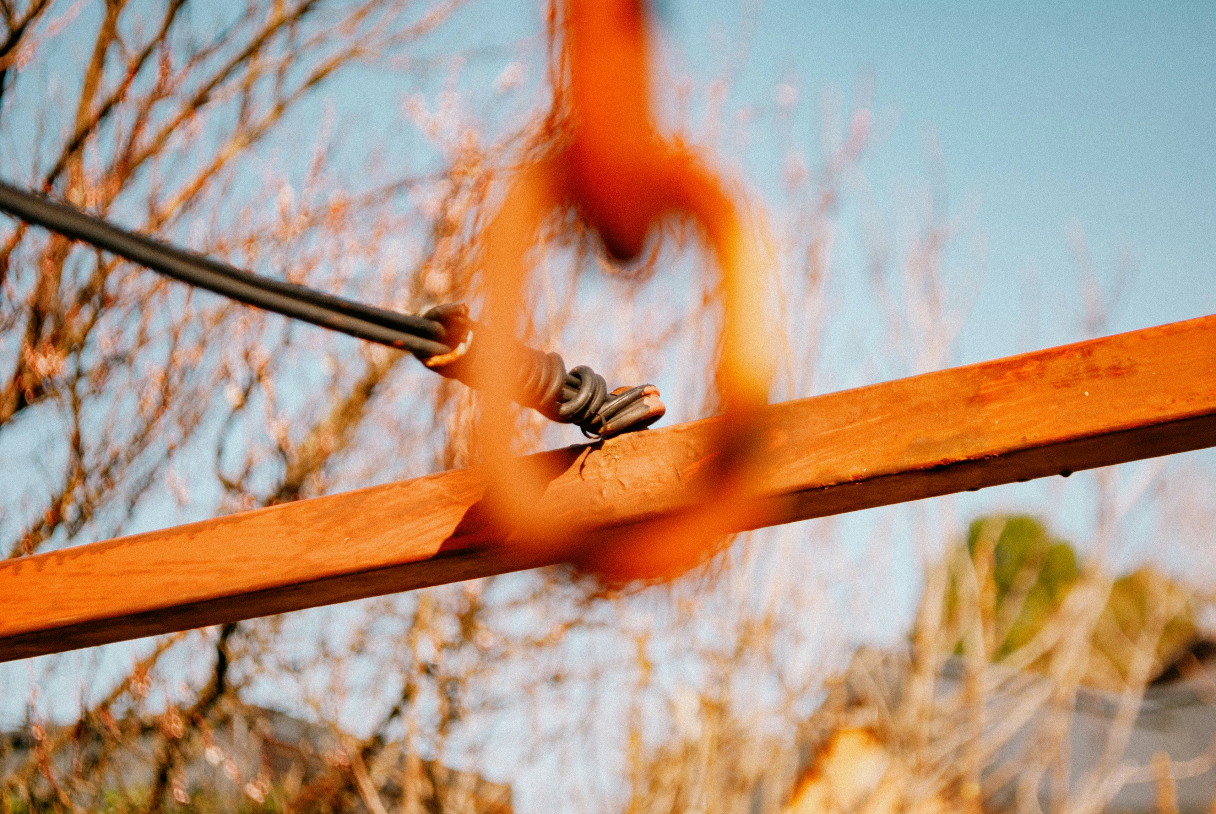 Looped in Orange: A Framing Blur of a Climbing Rope and Wood Beam