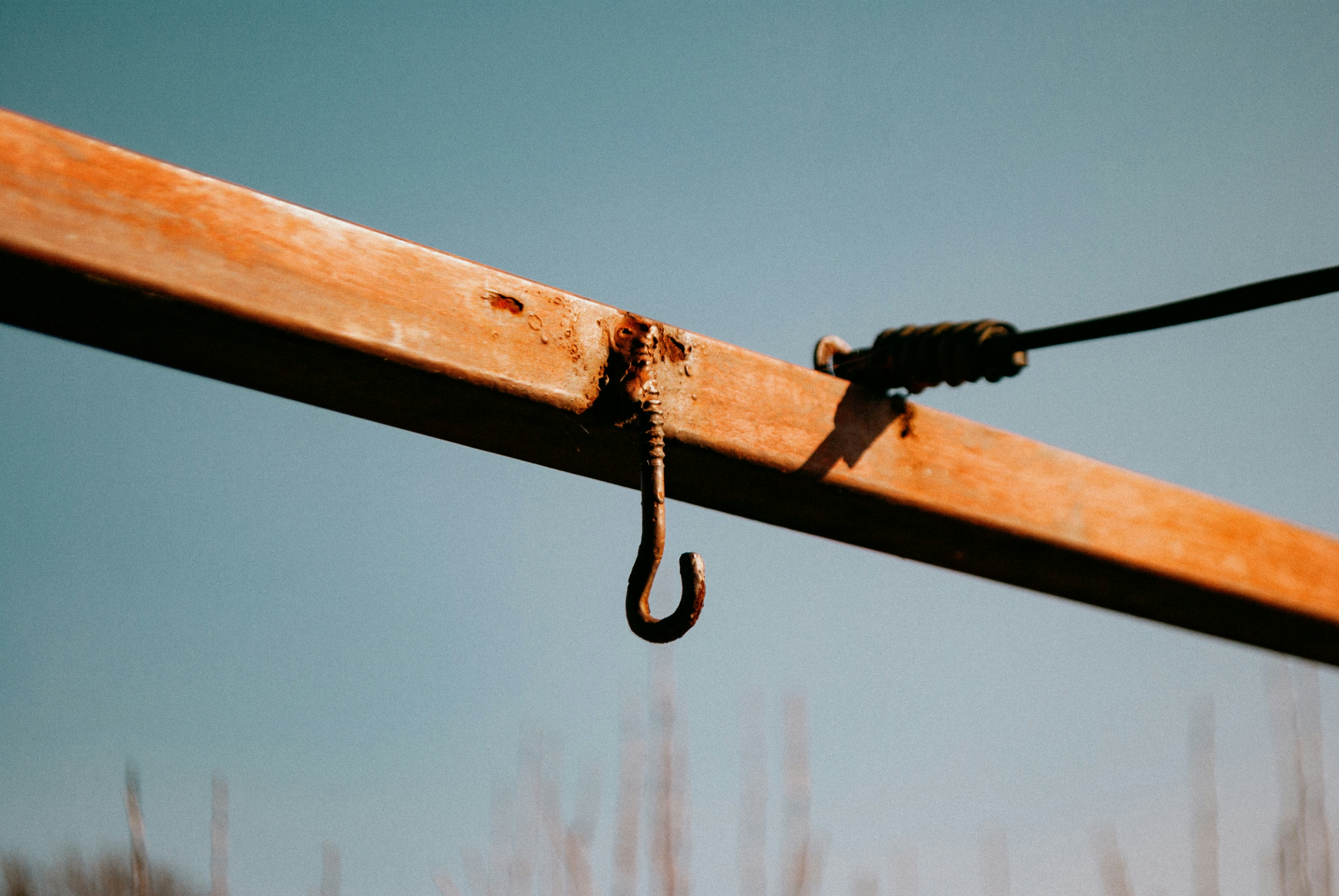 Rusted Hanger on a Weathered Beam Under Clear Sky