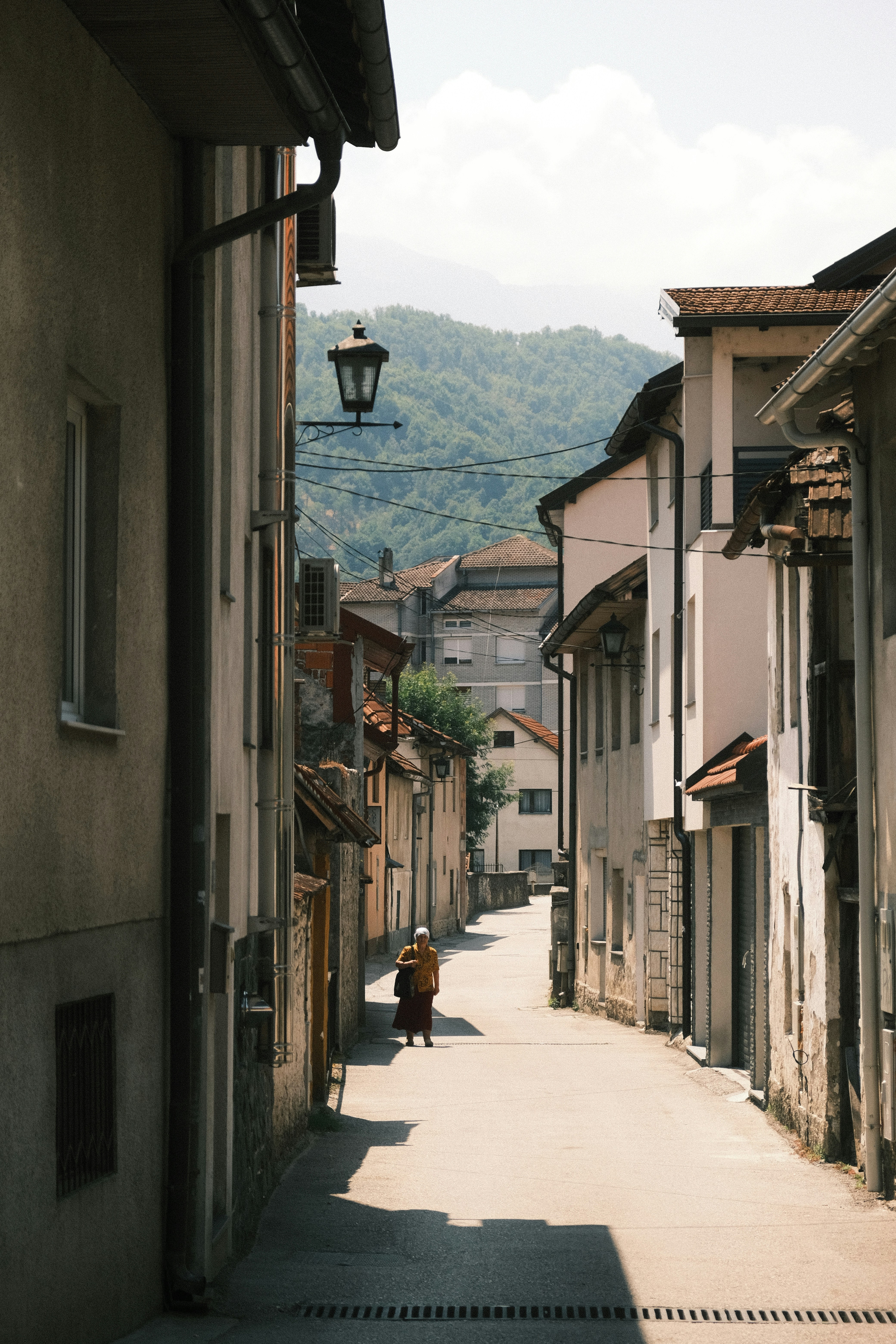 Sunlit Alley with a solitary traveler