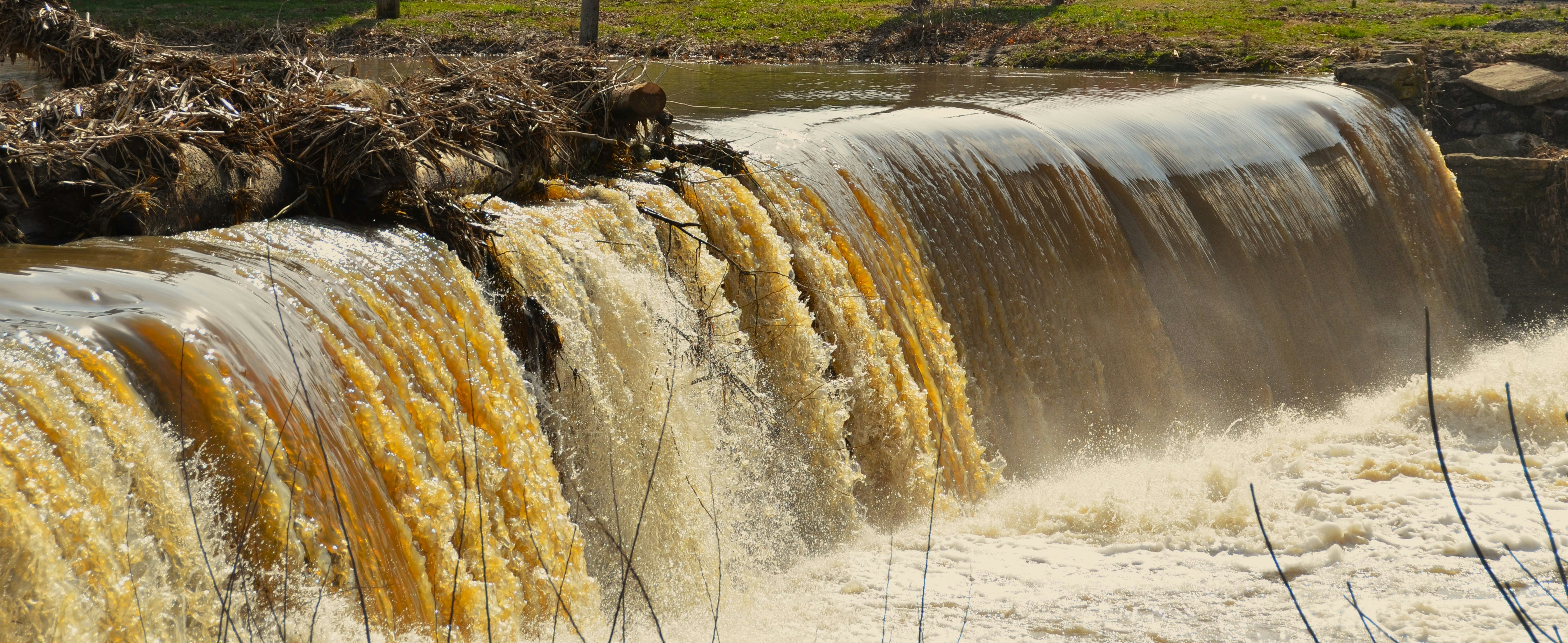 Rushing Curtain: Golden Waterfall Over a Wide River