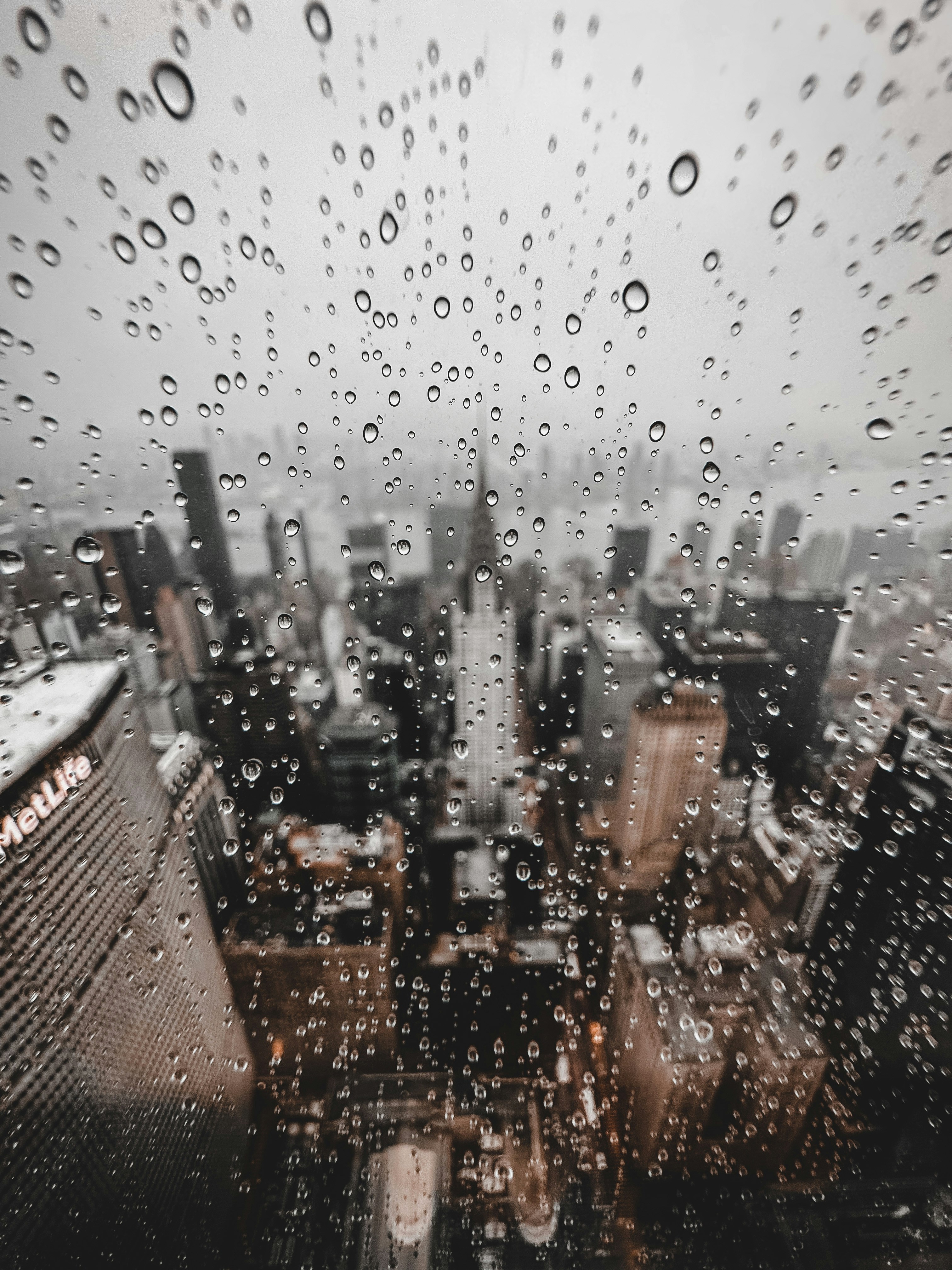 Rain-streaked skyline: droplets cling to glass above a misty metropolis