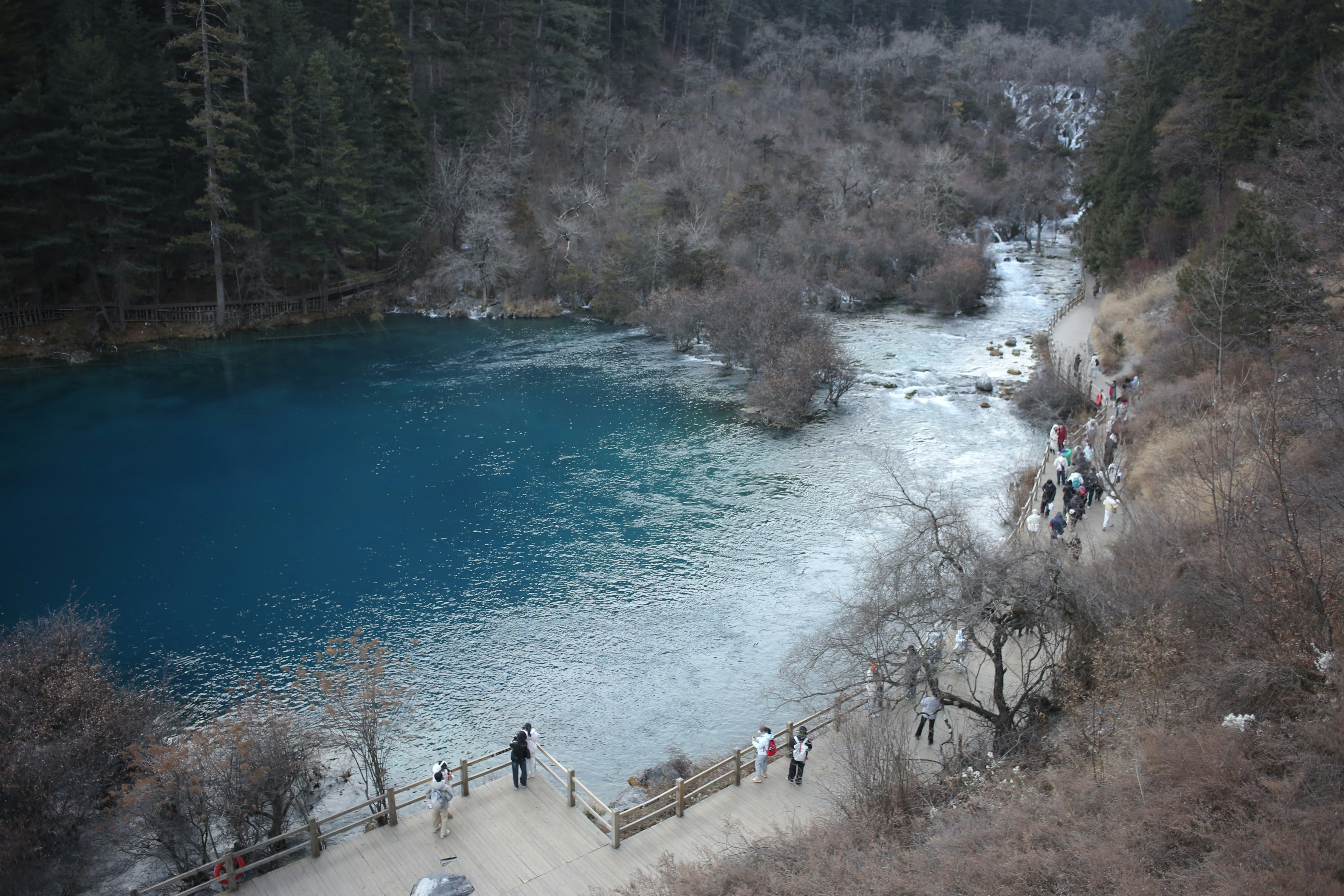 Azure Rim: People Walk a Boardwalk Beside a Glacial Blue Lake