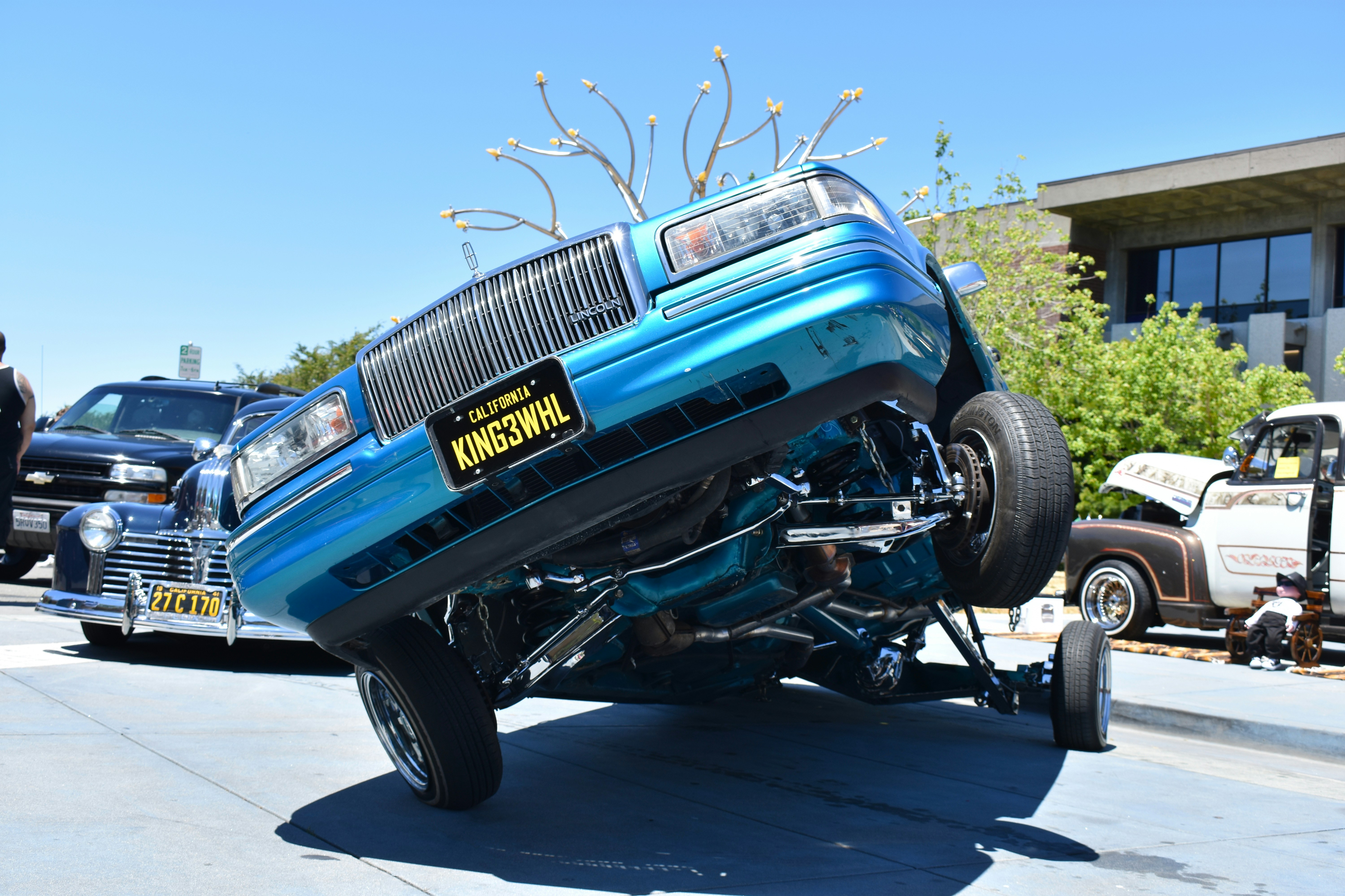 Blue custom pickup on a dynamic tilt during a public car show