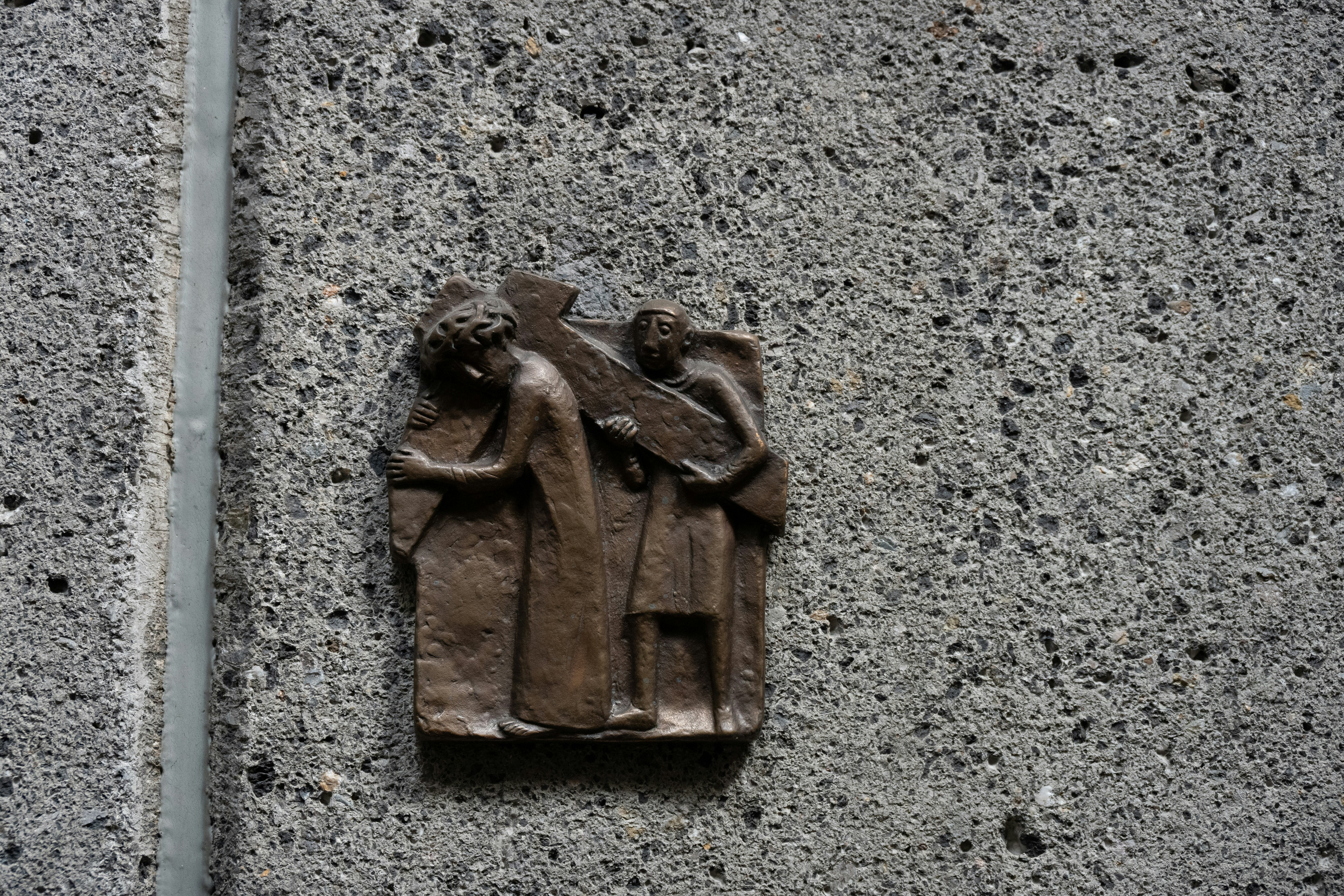Bas-relief on concrete: a three-figure moment embedded in stone