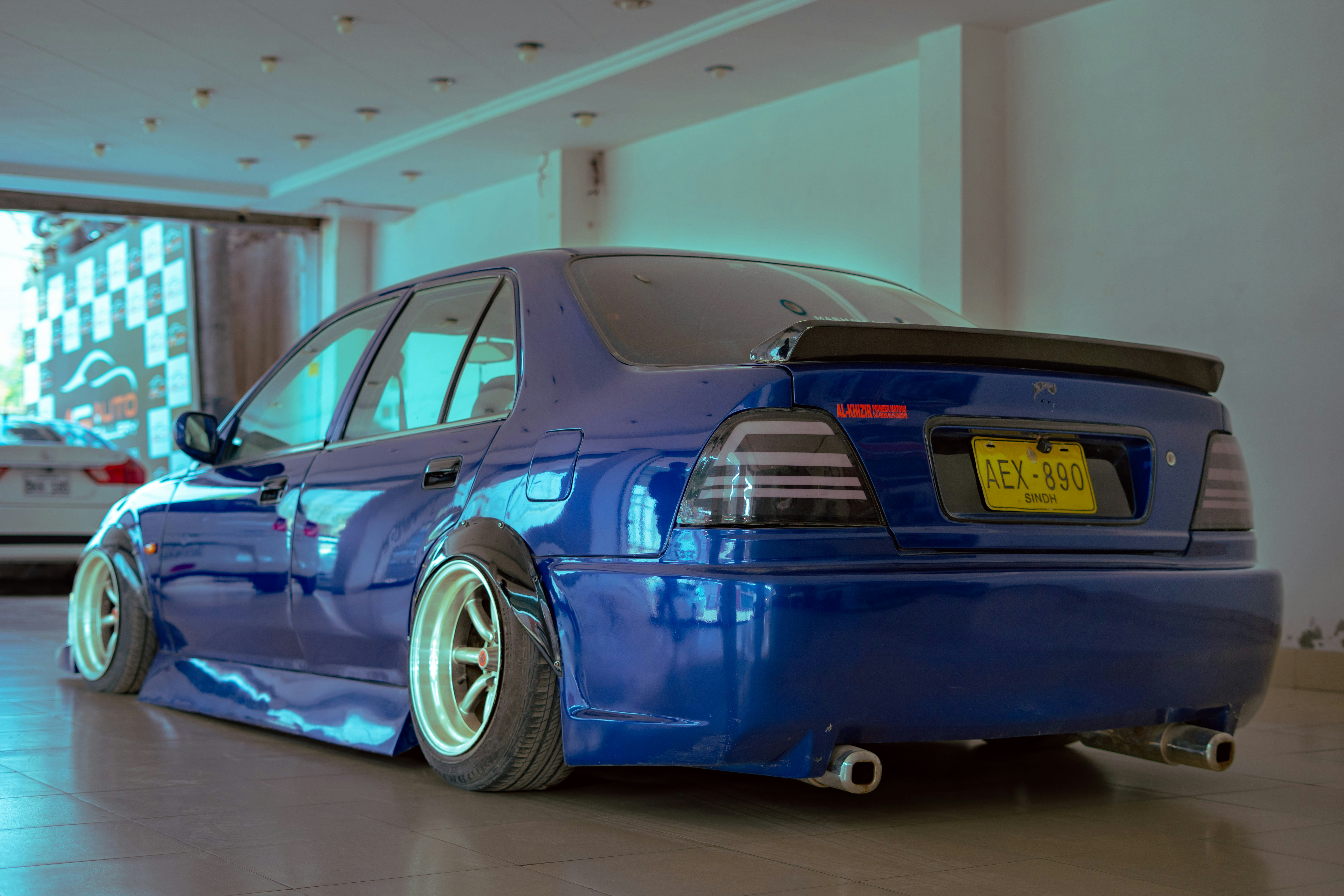 Low-Riddled Drift: A Custom Blue Sedan in an Indoor Gallery Cutout