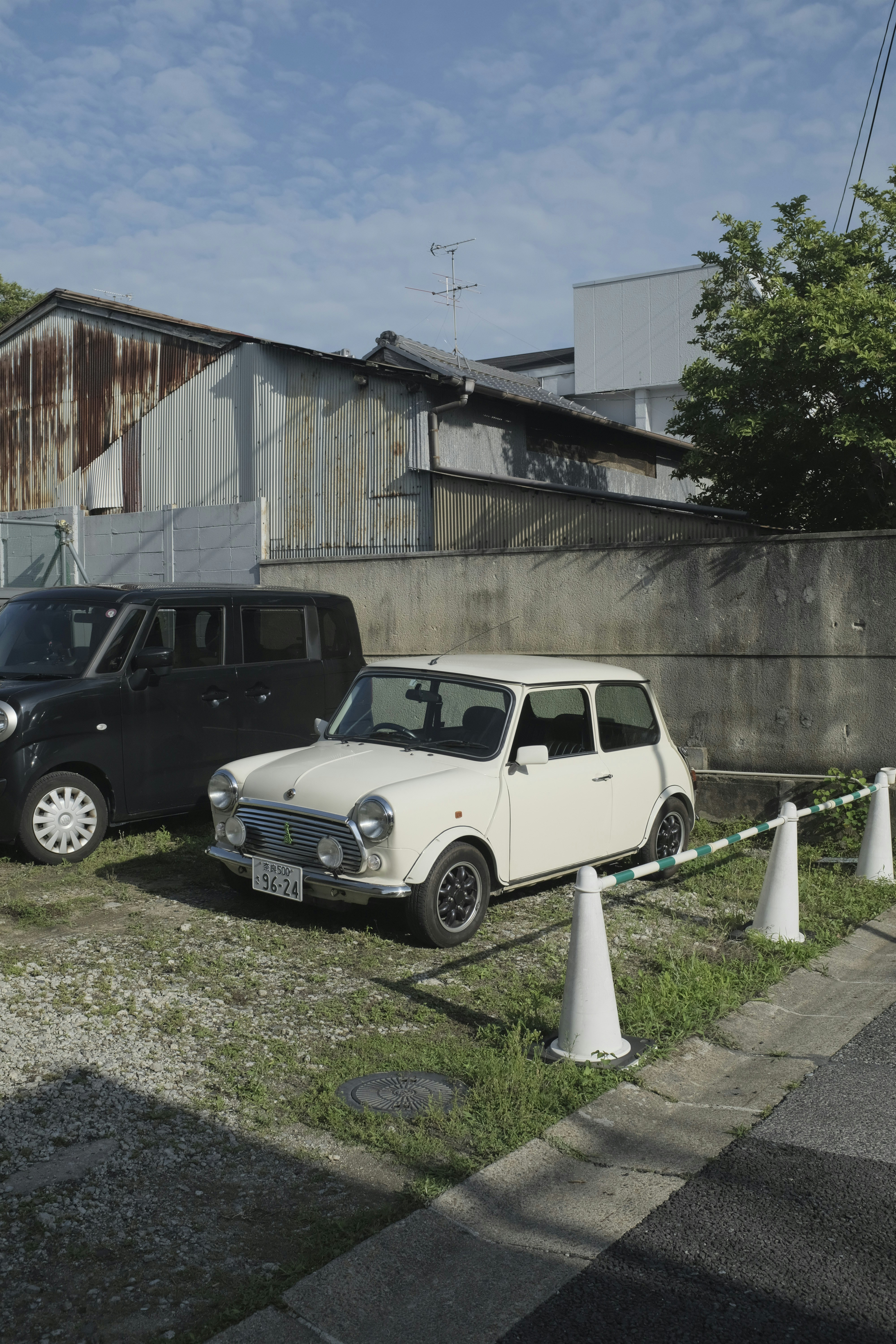 Vintage Mini in a Sunlit Lot by a Worn Factory Wall