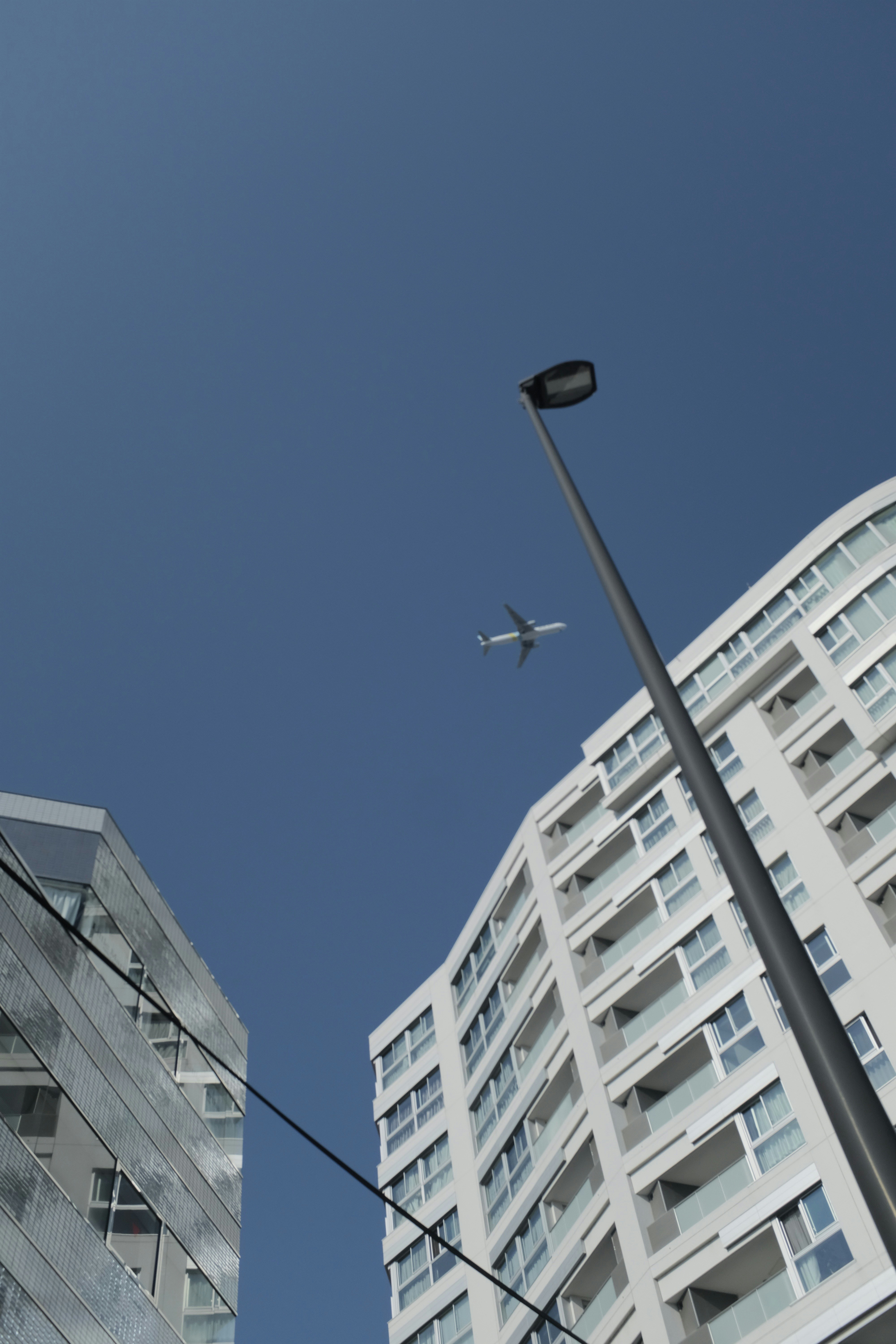 Skyscraper Angled Against a Clear Sky with a Passing Plane