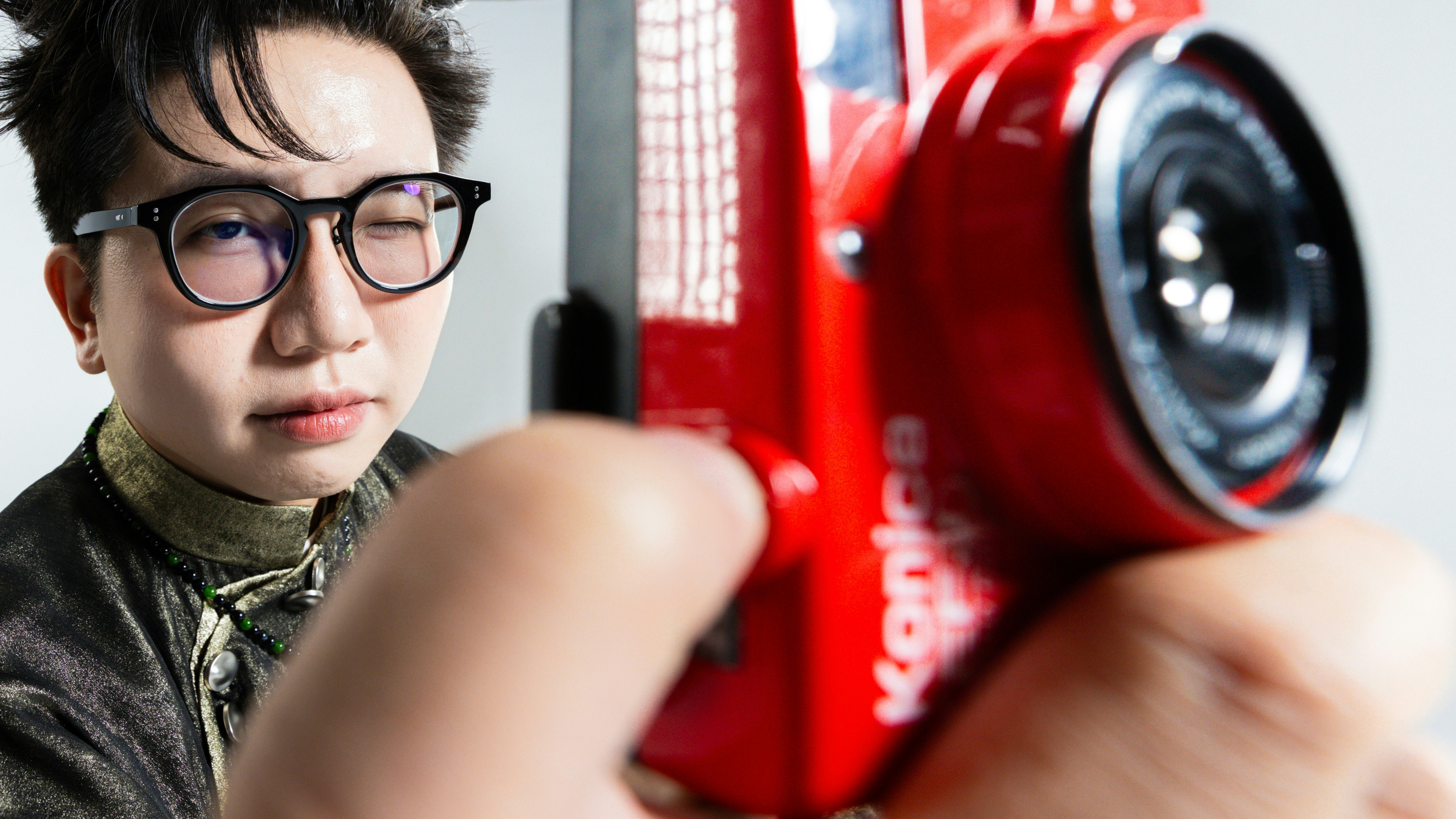 Close-Up of a Young Filmmaker Previewing a Red Toy Camera
