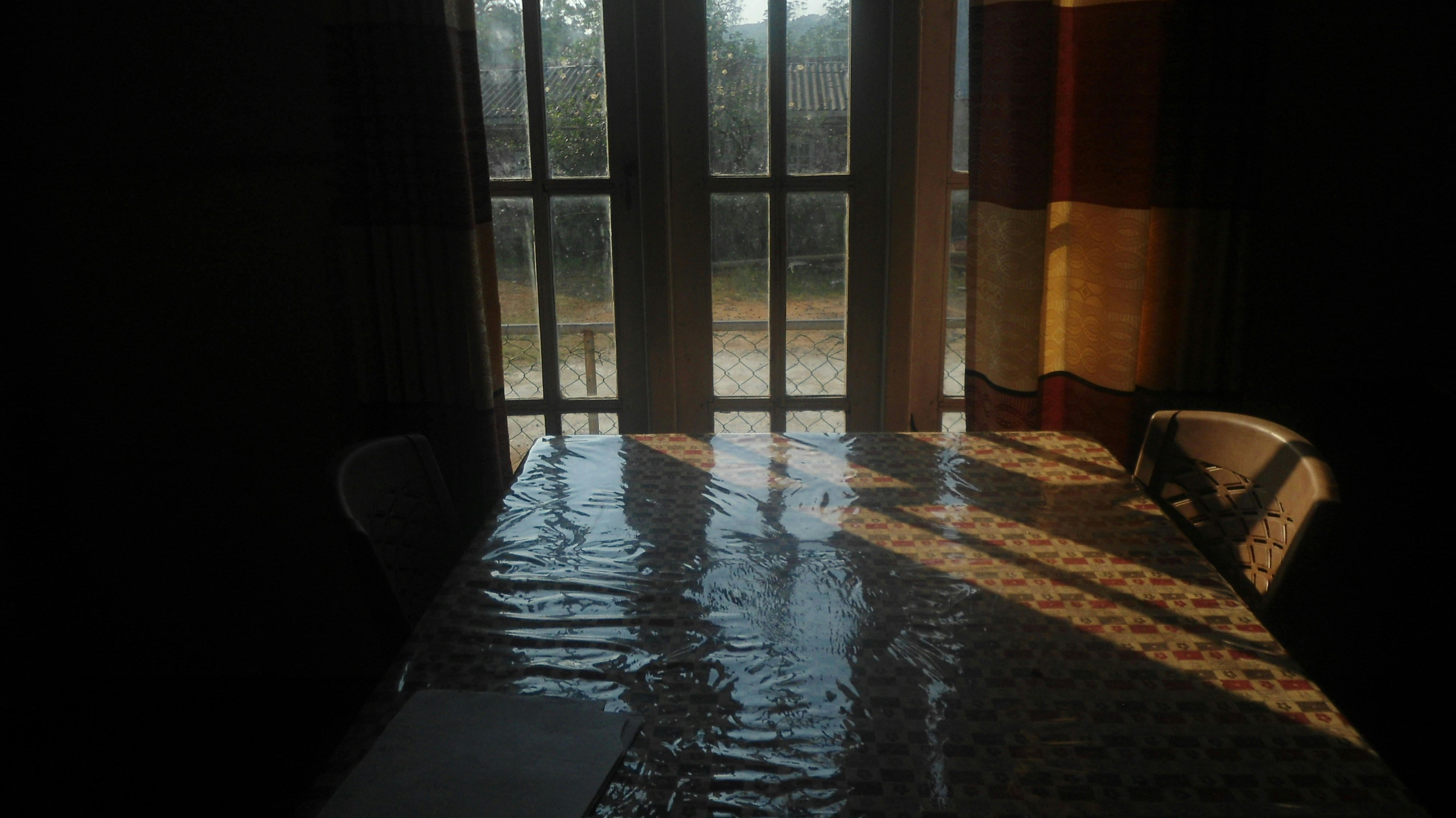 Sunlight streams across a table with chairs.