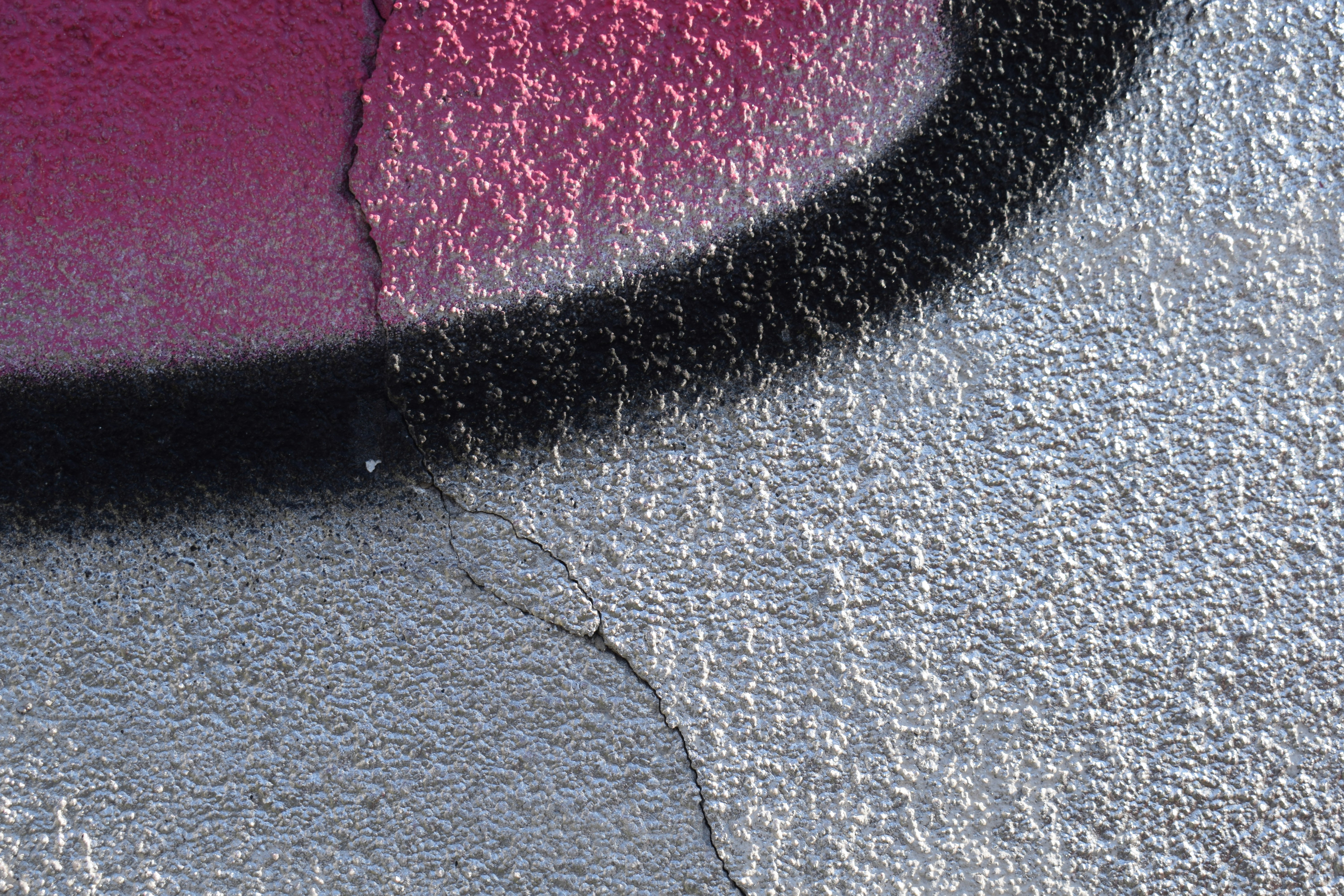 Cracked Concrete Echoes the Curve of Violet Graffiti