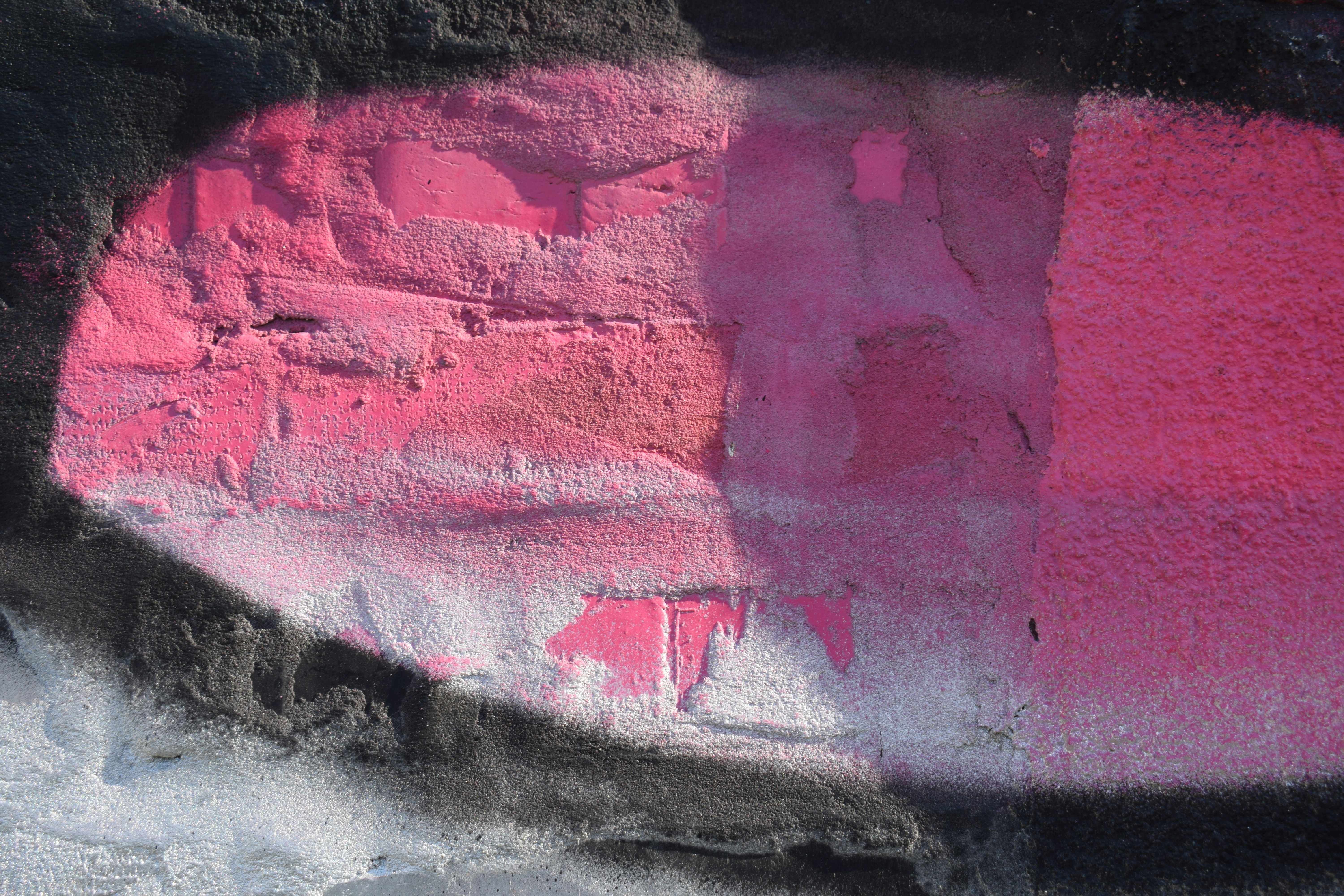Pink graffiti fade over weathered concrete