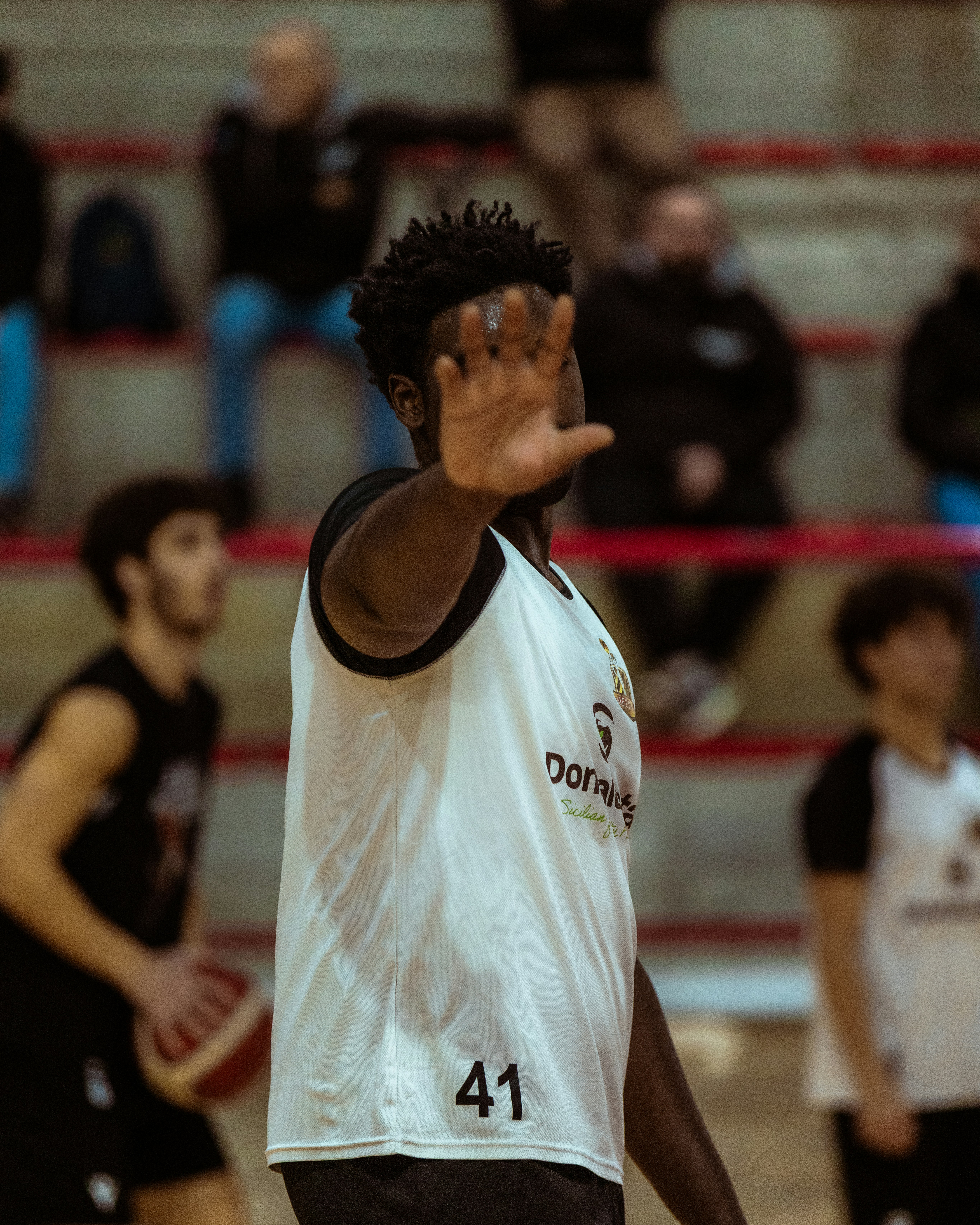 Momentum in Motion: A Basketball Player Extends a Stopping Hand in a Gym