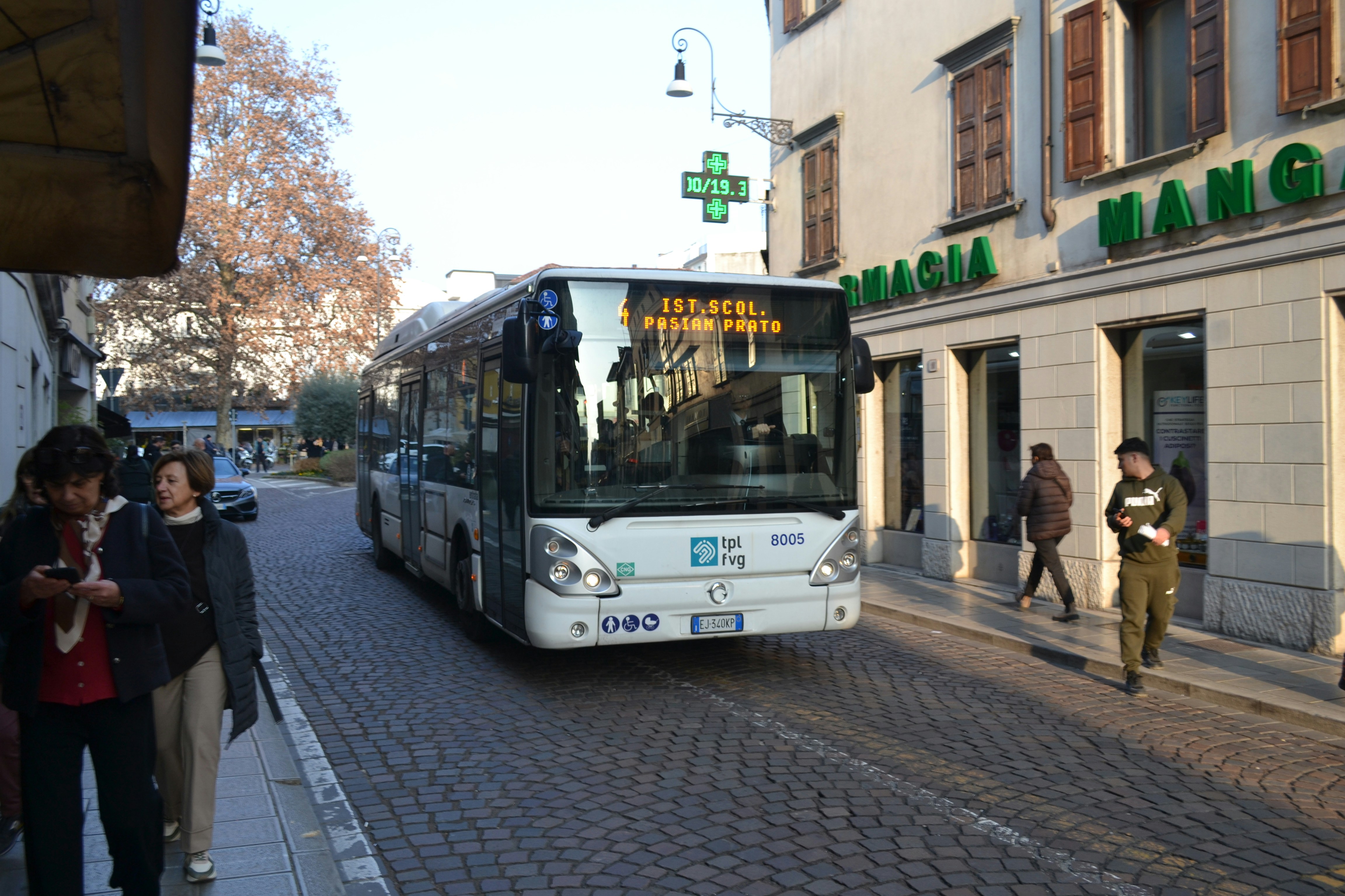 Bus at Narrow Cobblestone Street in Front of Pharmacy