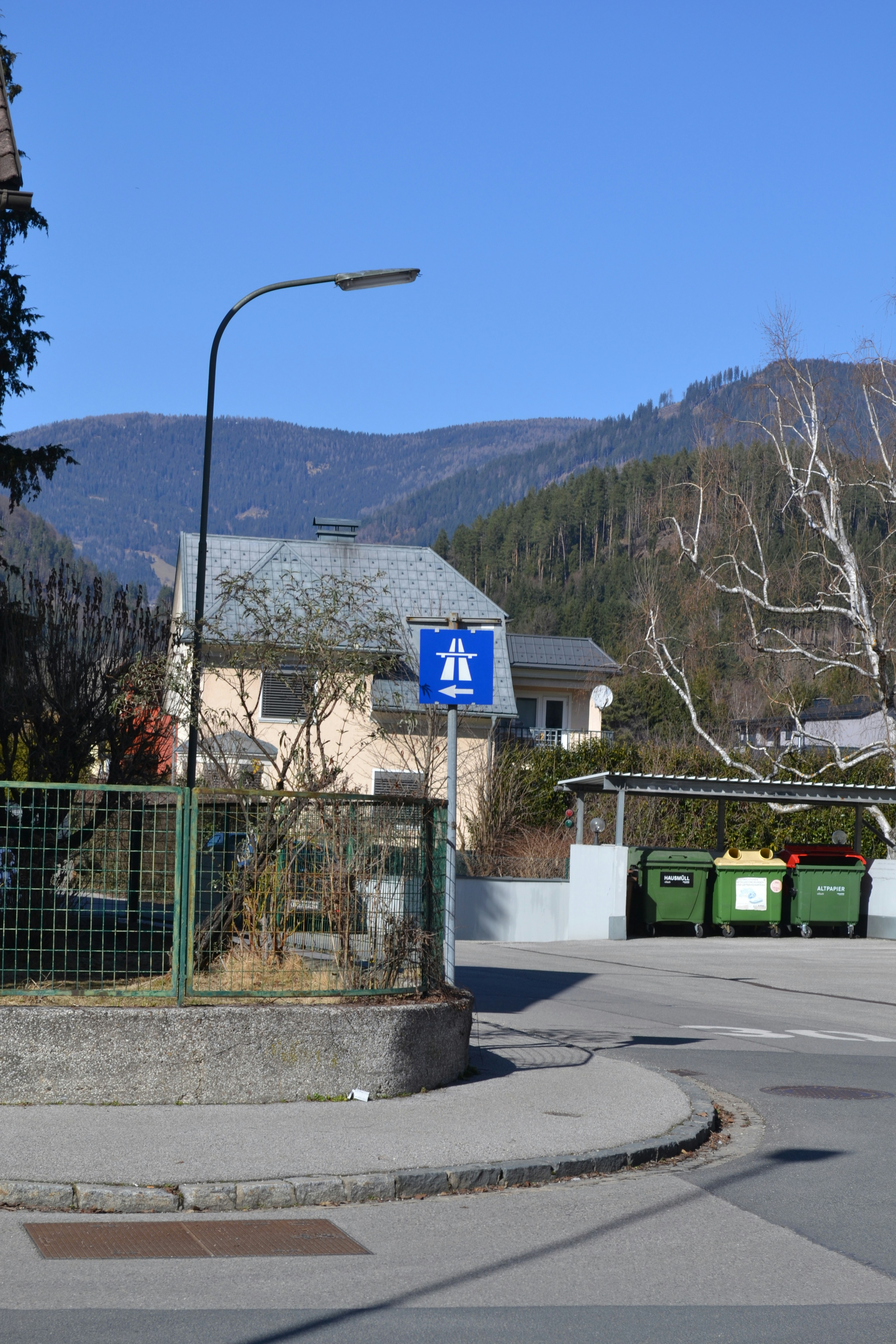 Street Corner with Recycling Bins Under a Quiet Blue Sky