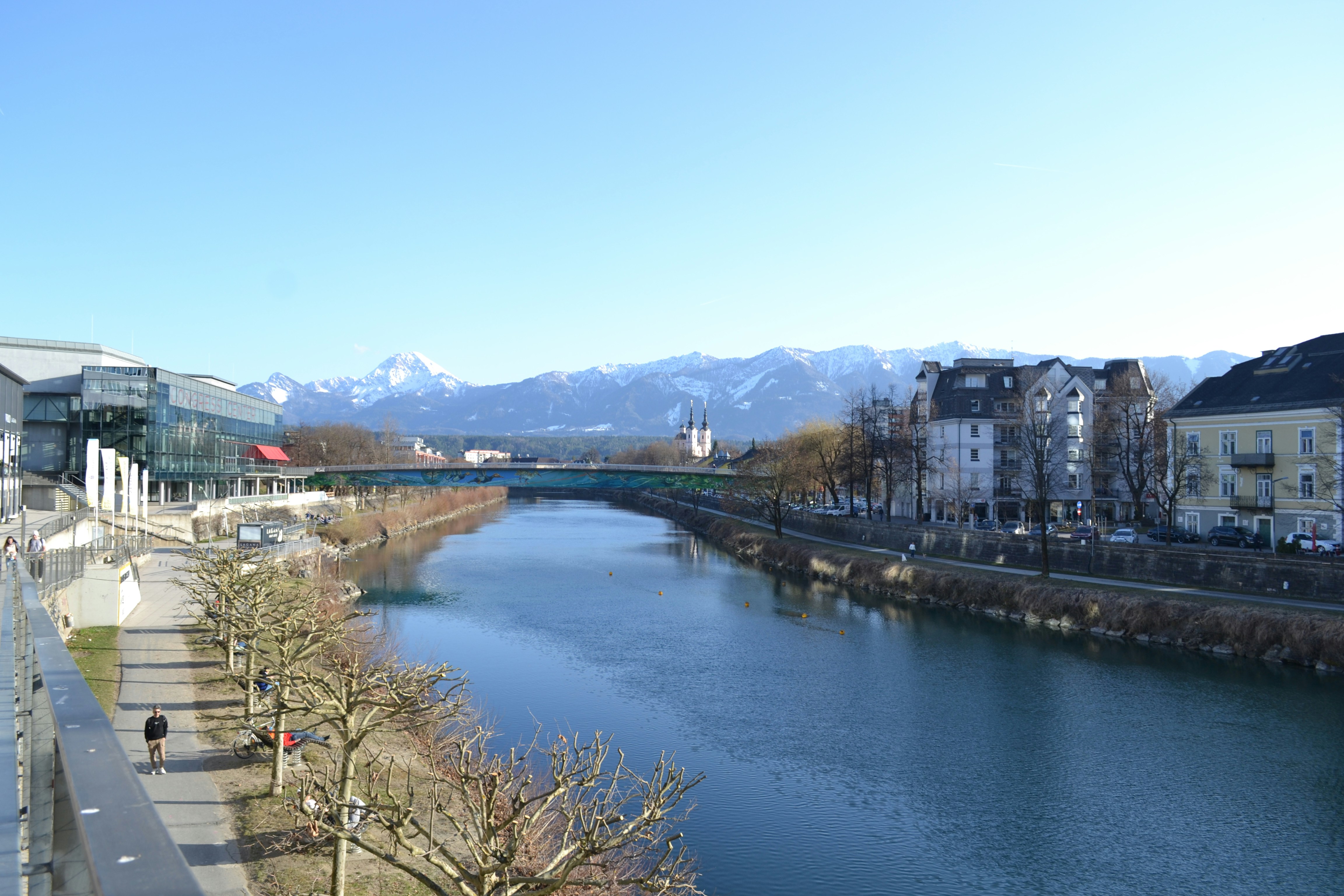 Snow-kissed Alps mirrored: a tranquil riverside town under a clear sky