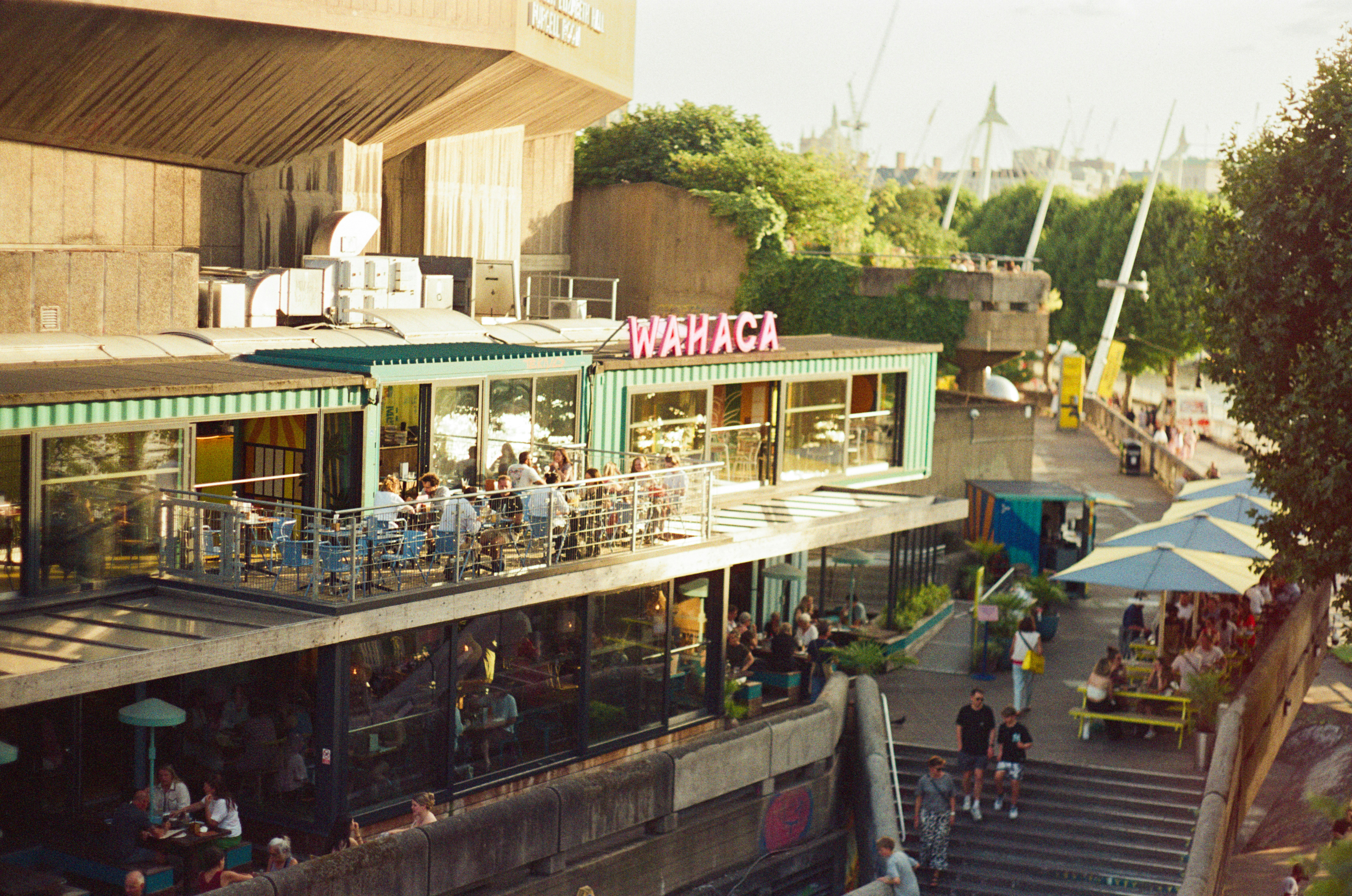 People dining and socializing on a sunny outdoor terrace.