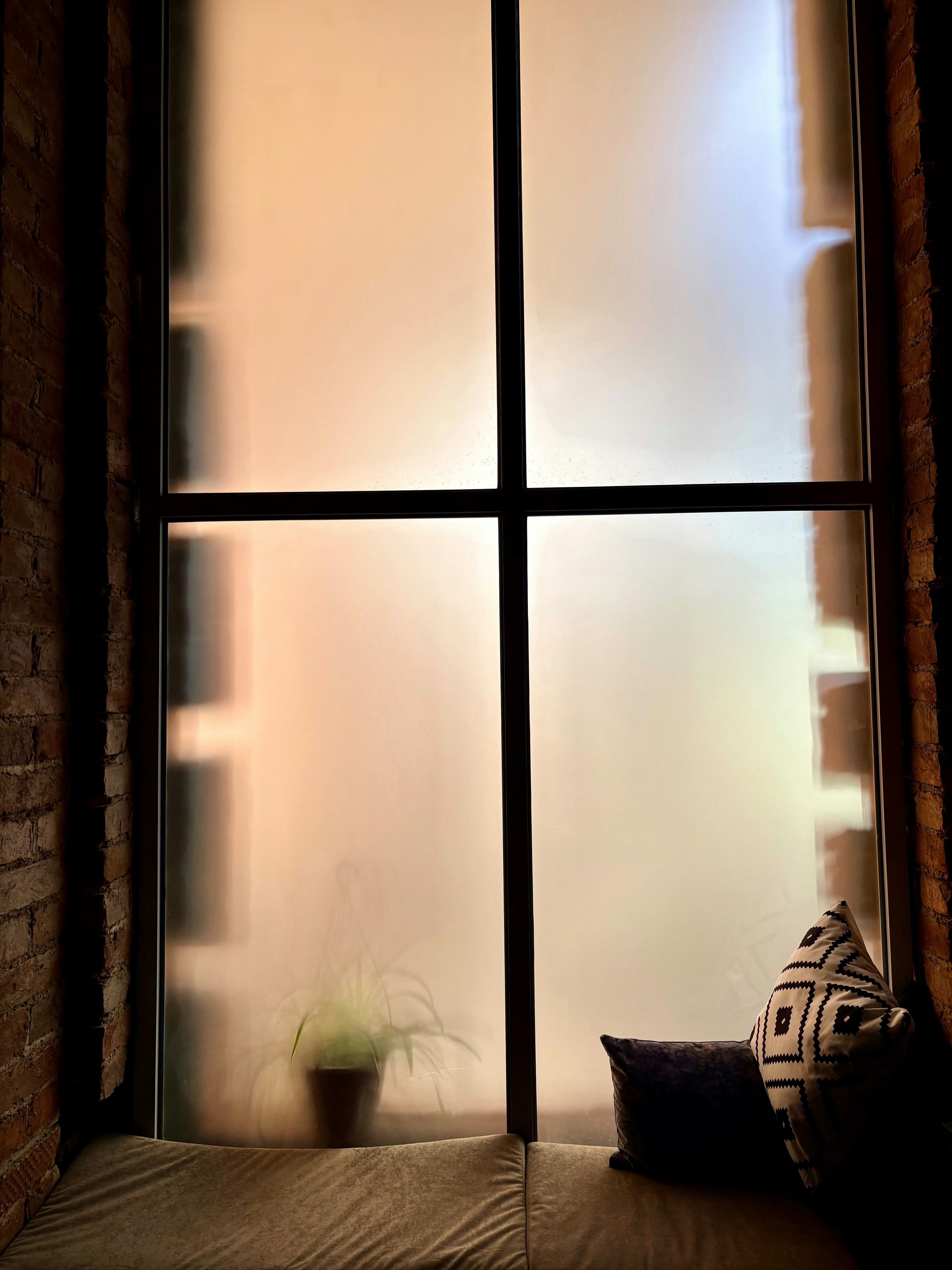 Sunlit loft nook with frosted window and corner seating